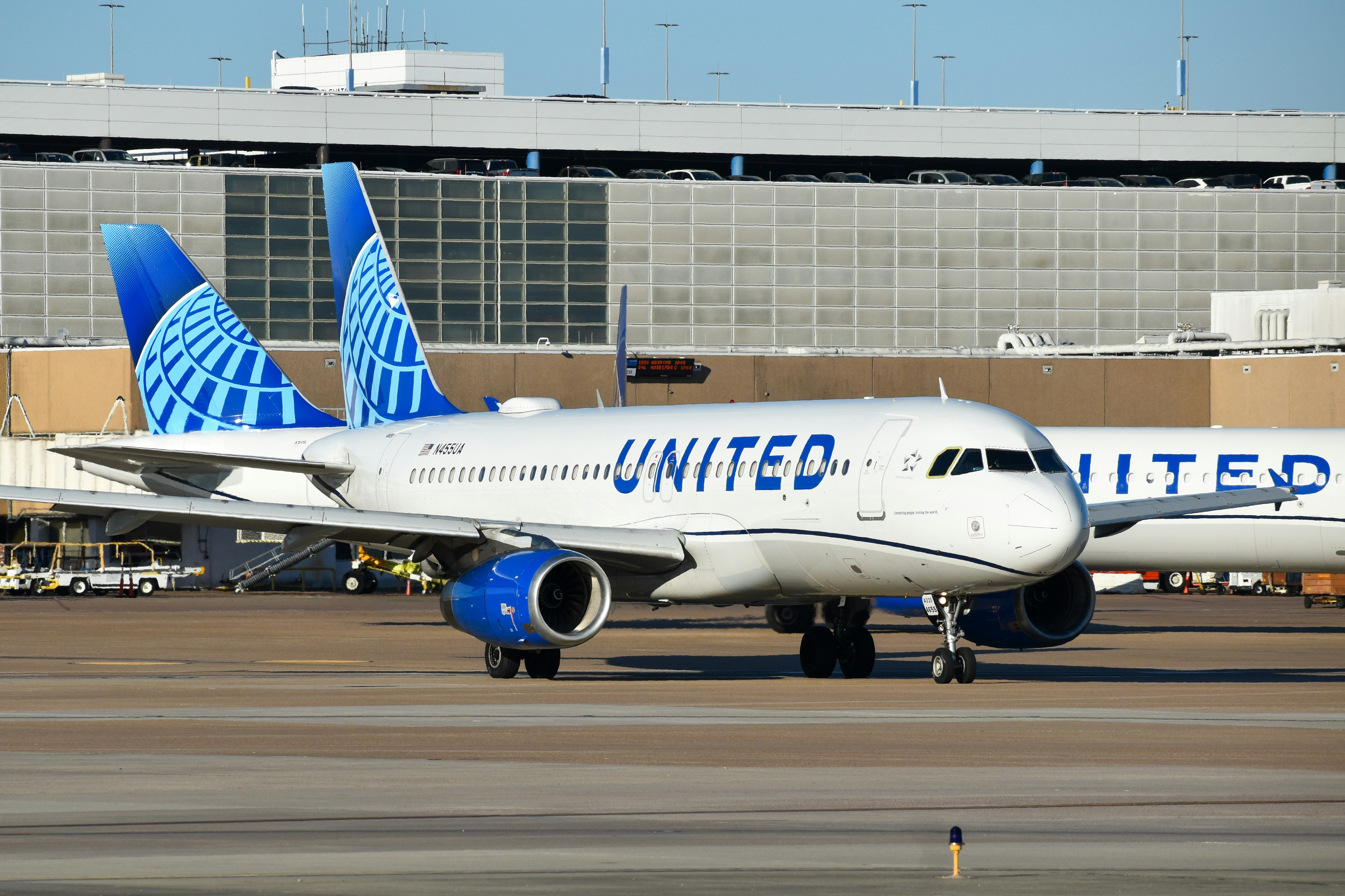 Passenger jet on the tarmac with terminal backdrop under clear skies.