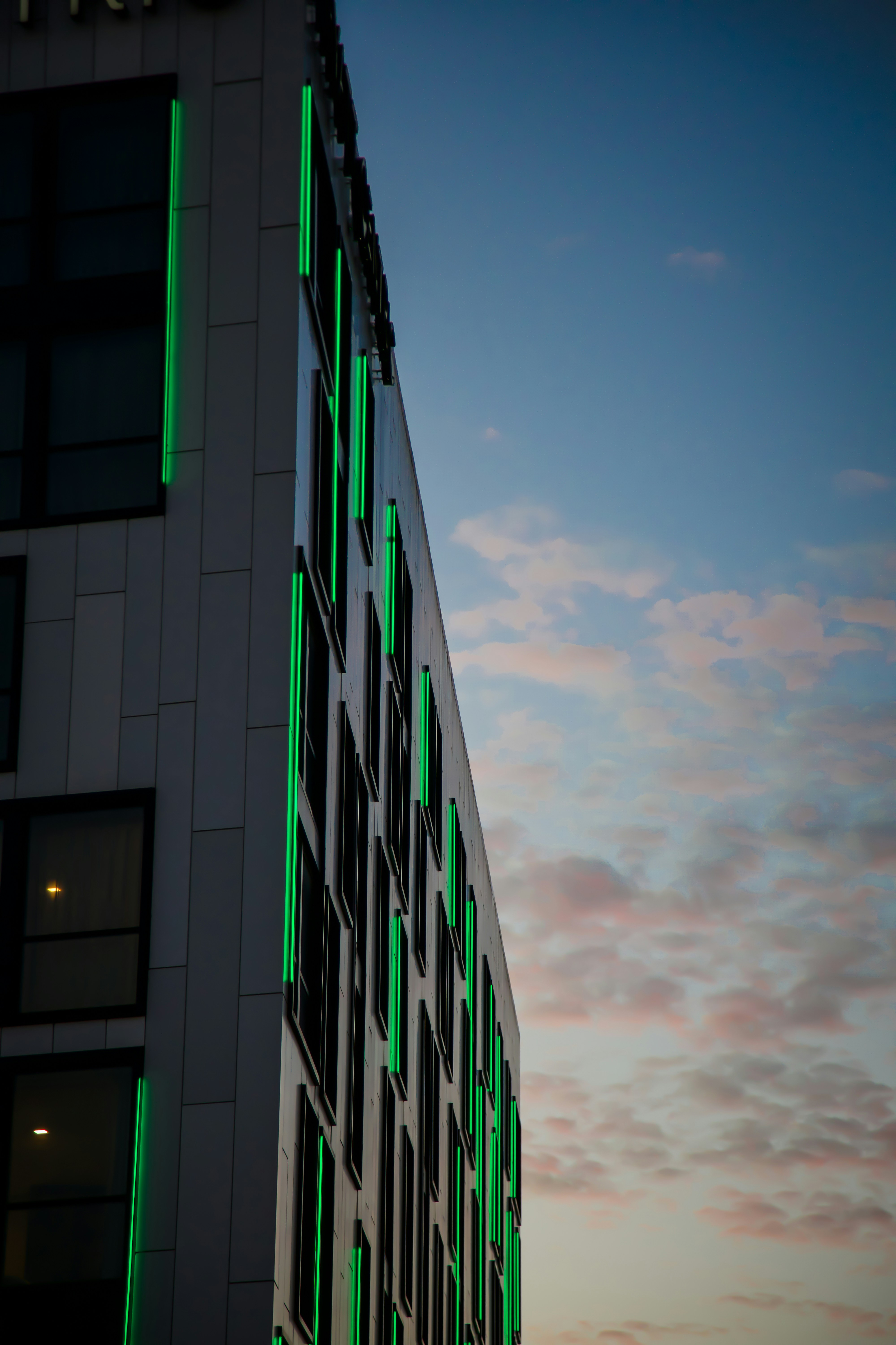 A tall building with a green light on it's side photo – Free Street ...