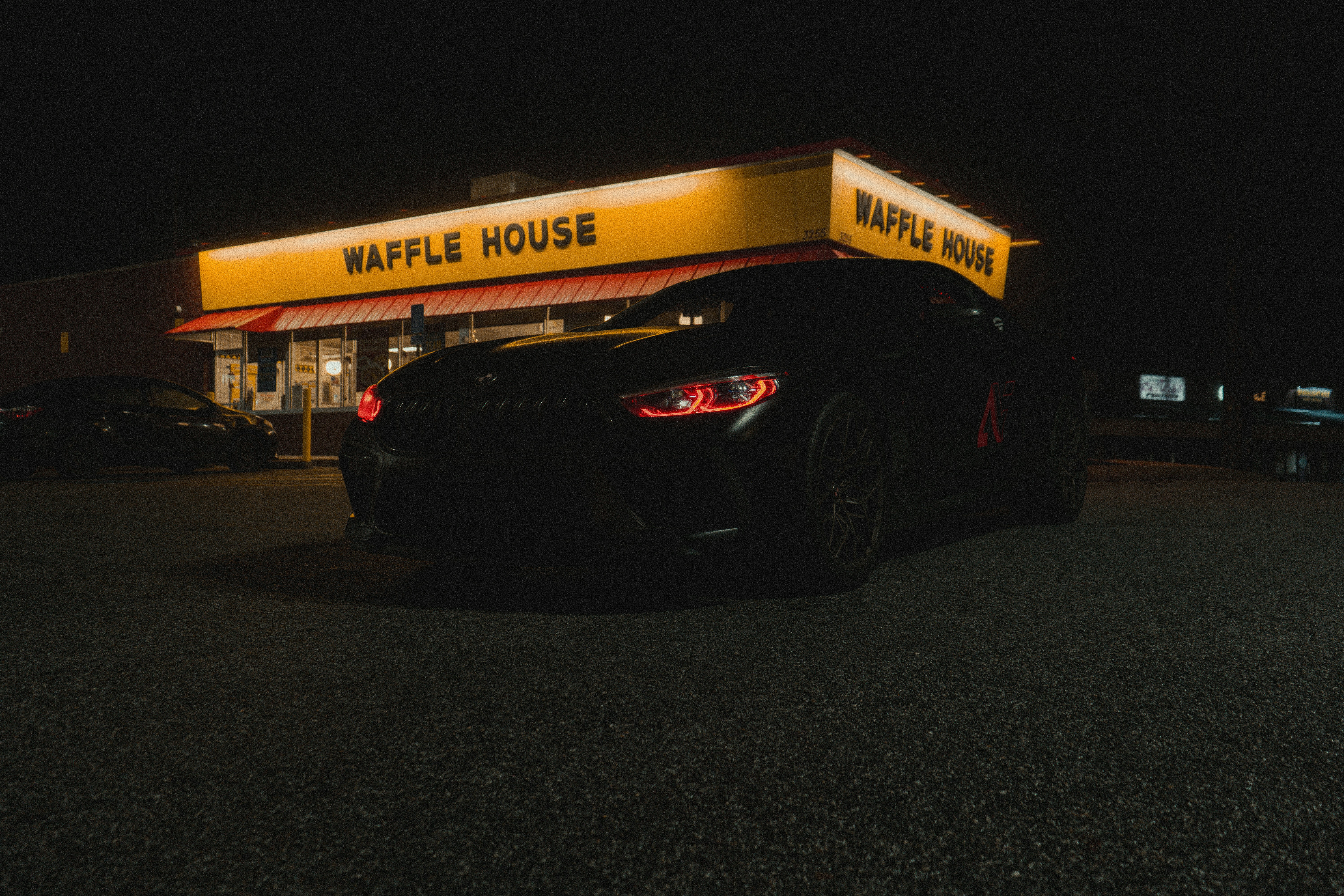 Midnight Run at the Neon Waffle House: A Sleek Car Under Amber Glow