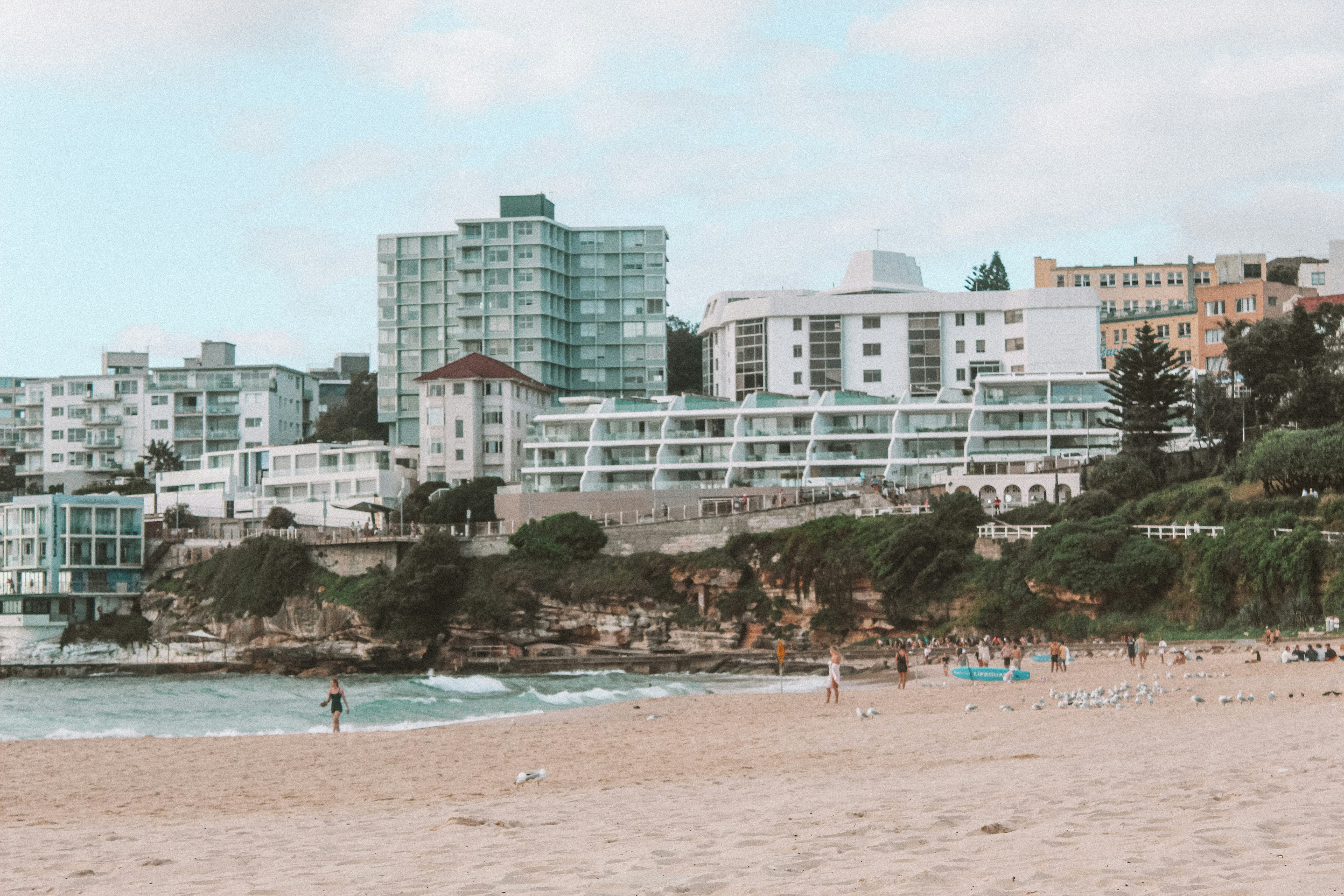 Modern coastal buildings overlooking a tranquil sandy beach, offering a perfect blend of urban living and seaside serenity.