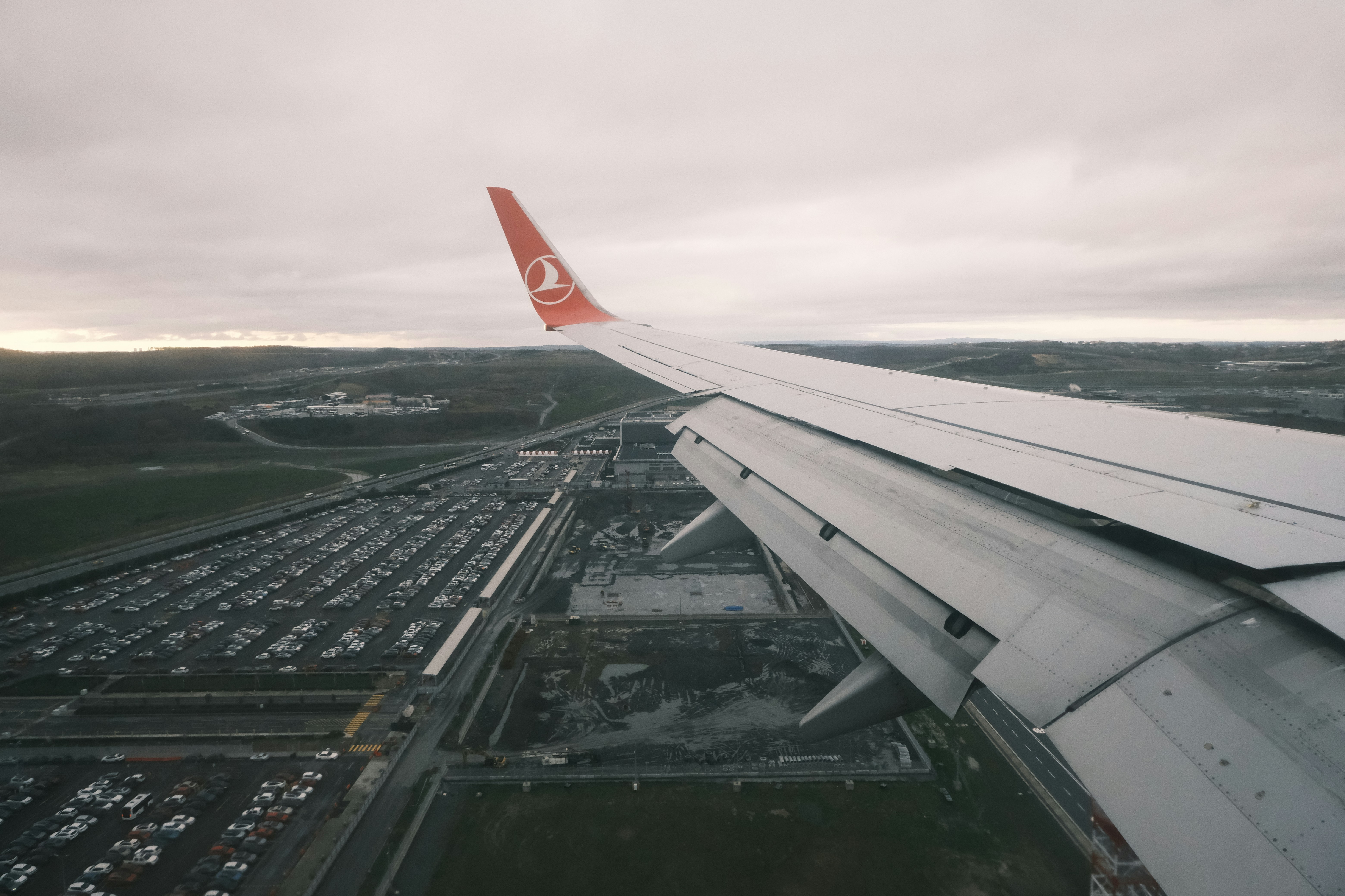 The wing of an airplane flying over a parking lot photo – Free Terminal ...