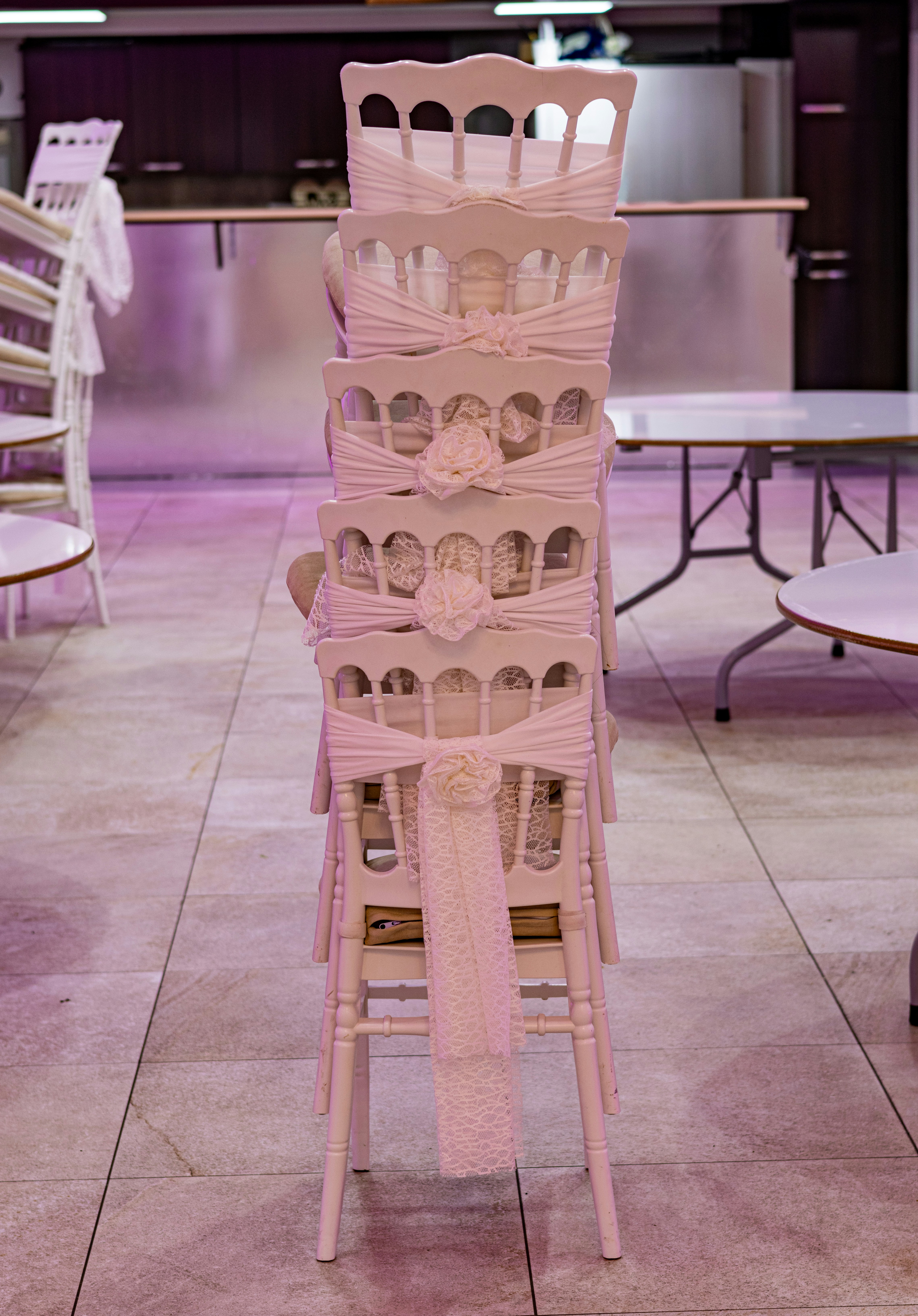 Towering Pink Drapes: Stacked Wedding Chairs in Soft Illumination