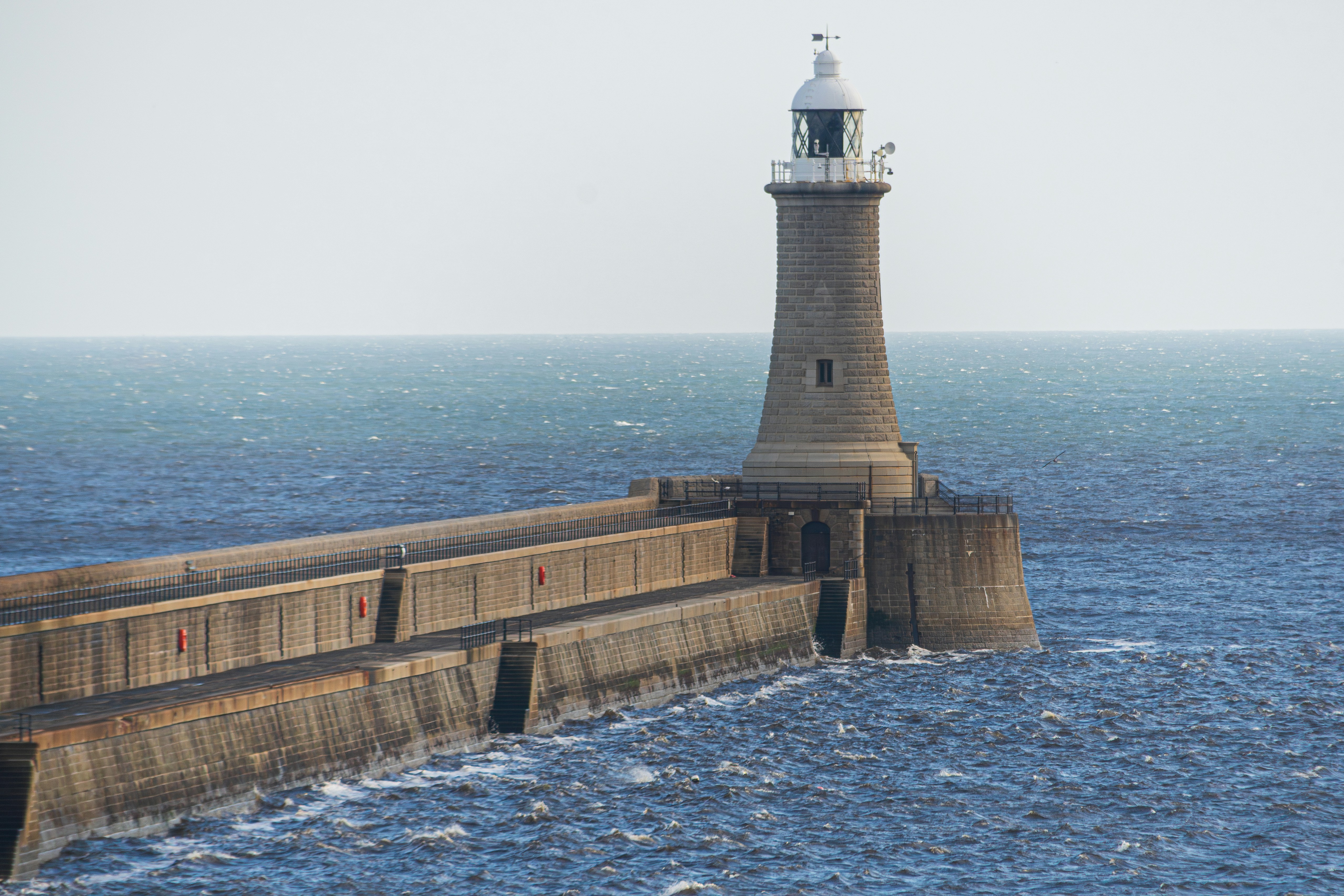 A light house sitting on top of a pier next to the ocean photo – Free ...