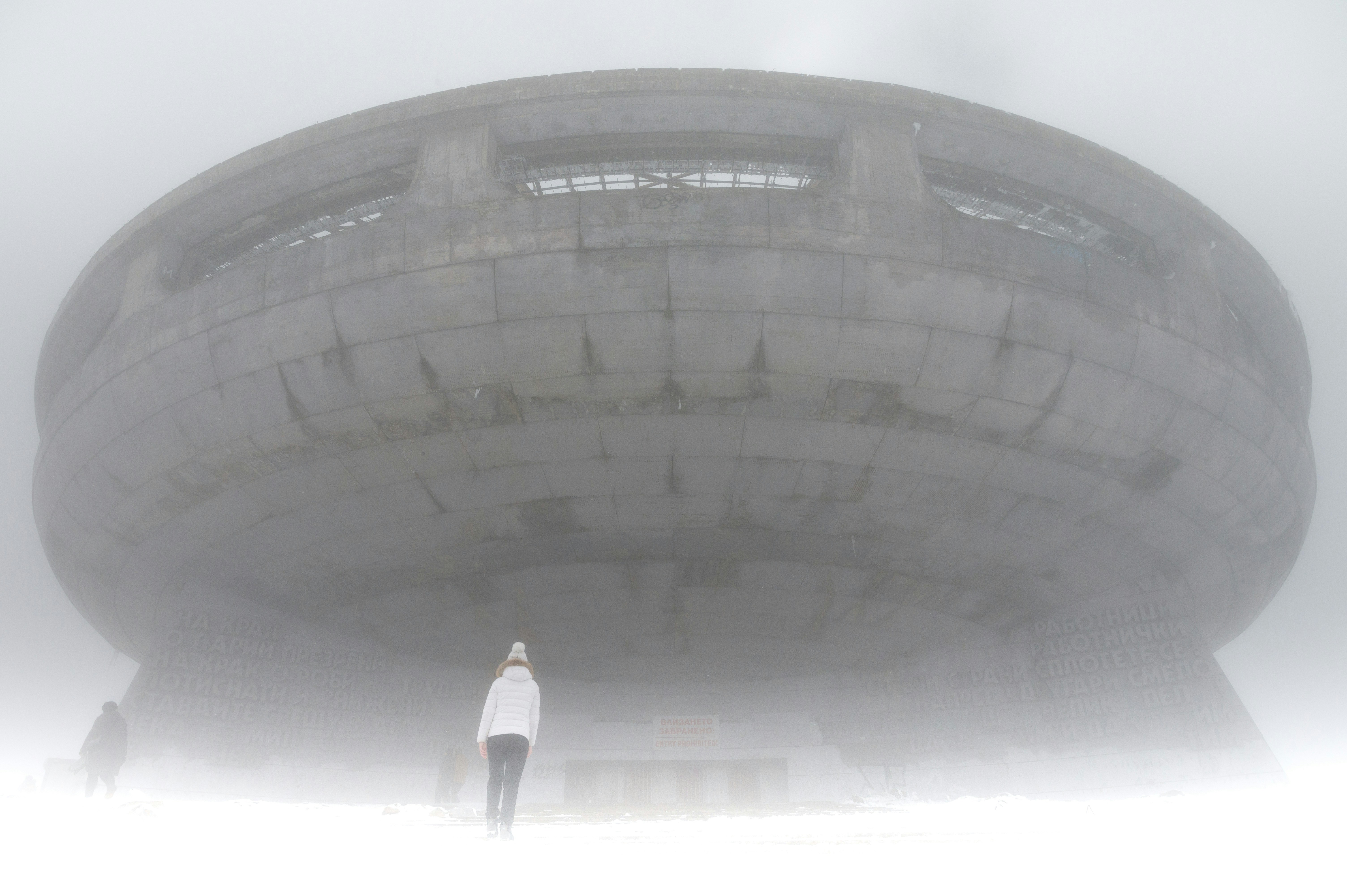 Mistbound Colossus: A lone figure beneath the circular concrete form