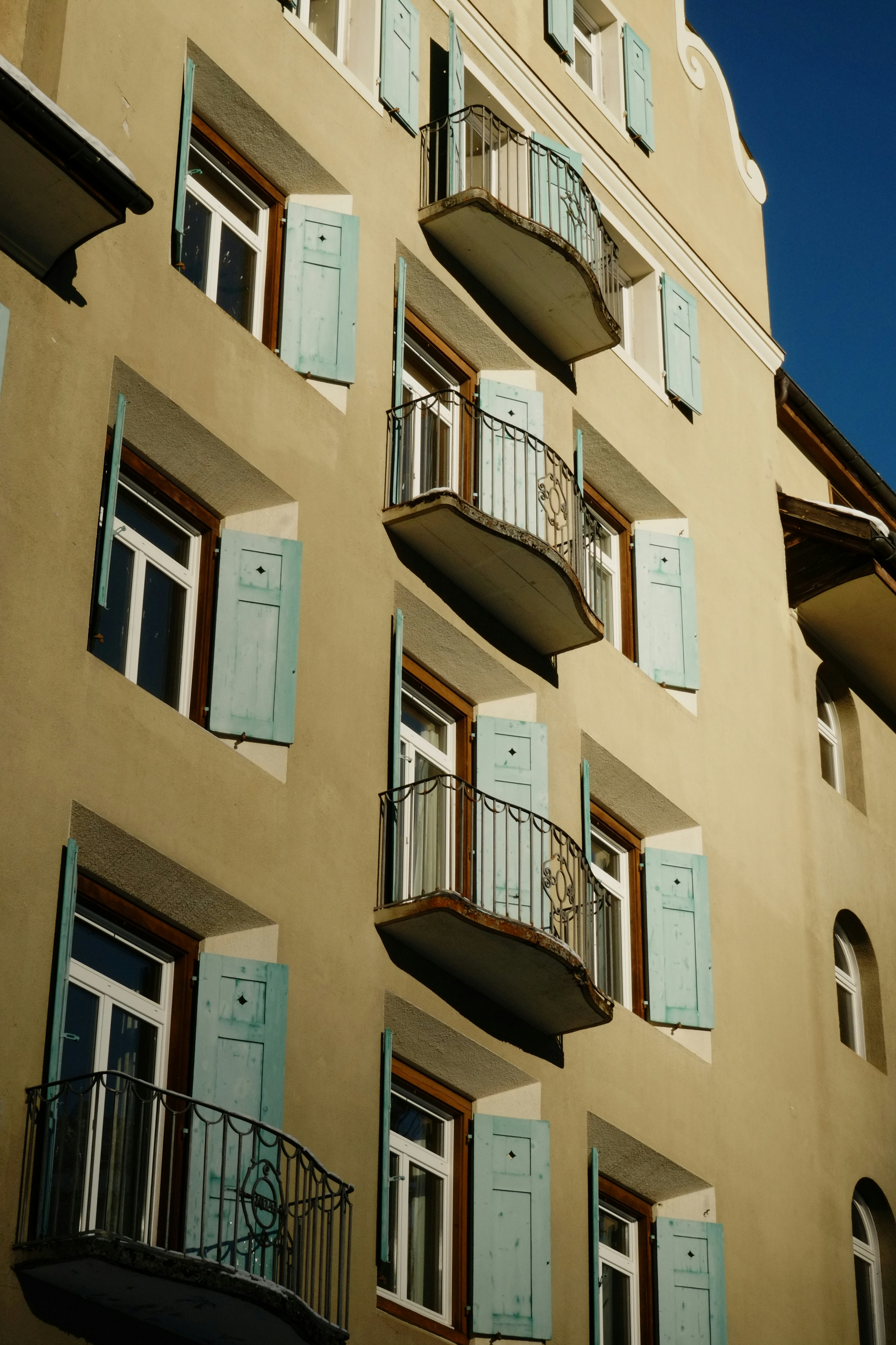 A tall building with blue shutters and balconies photo – Free Scuol ...