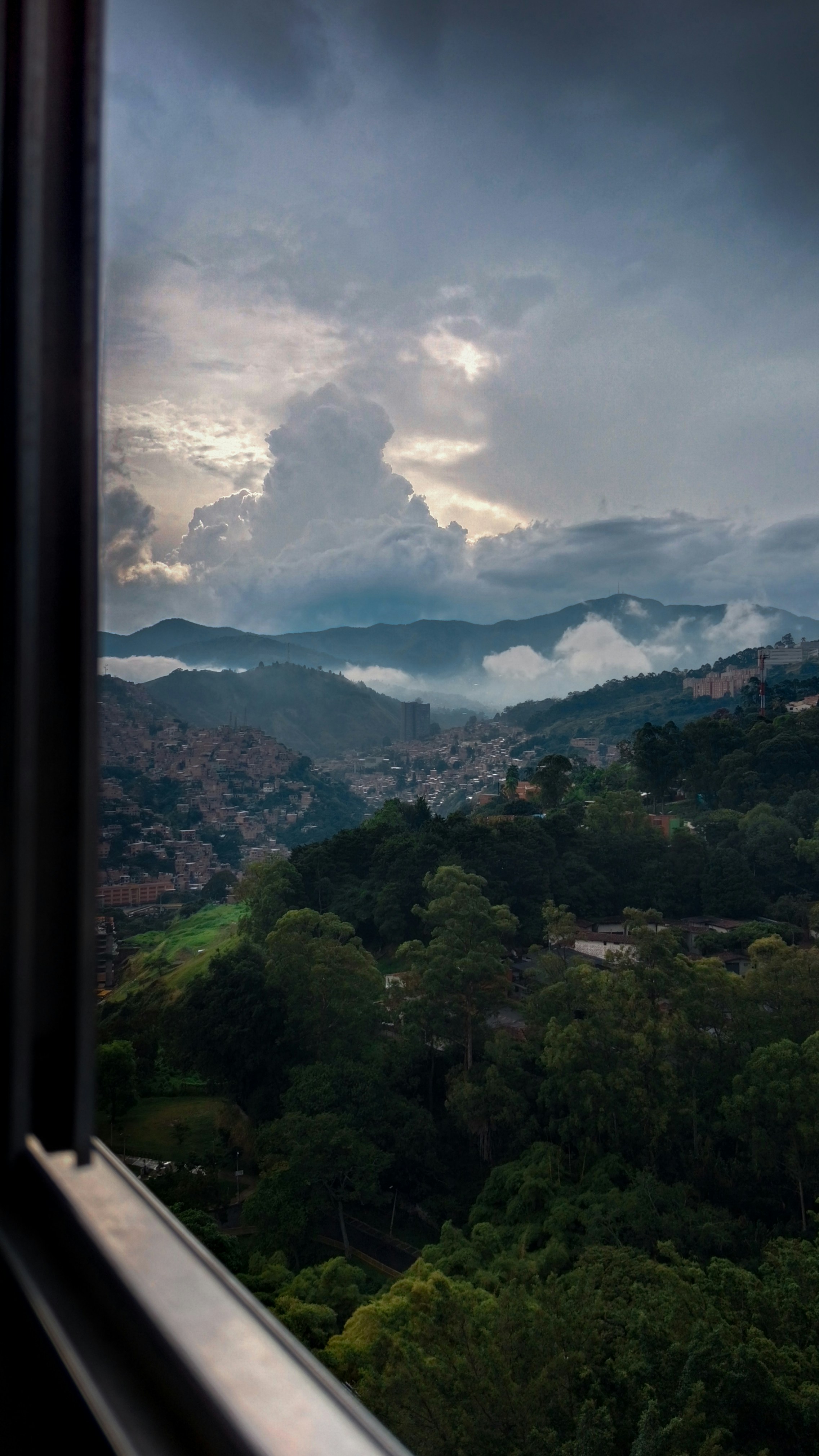 The city of Medellín on a cloudy day, with clouds hugging the mountains, showcasing the blend of nature and urban life