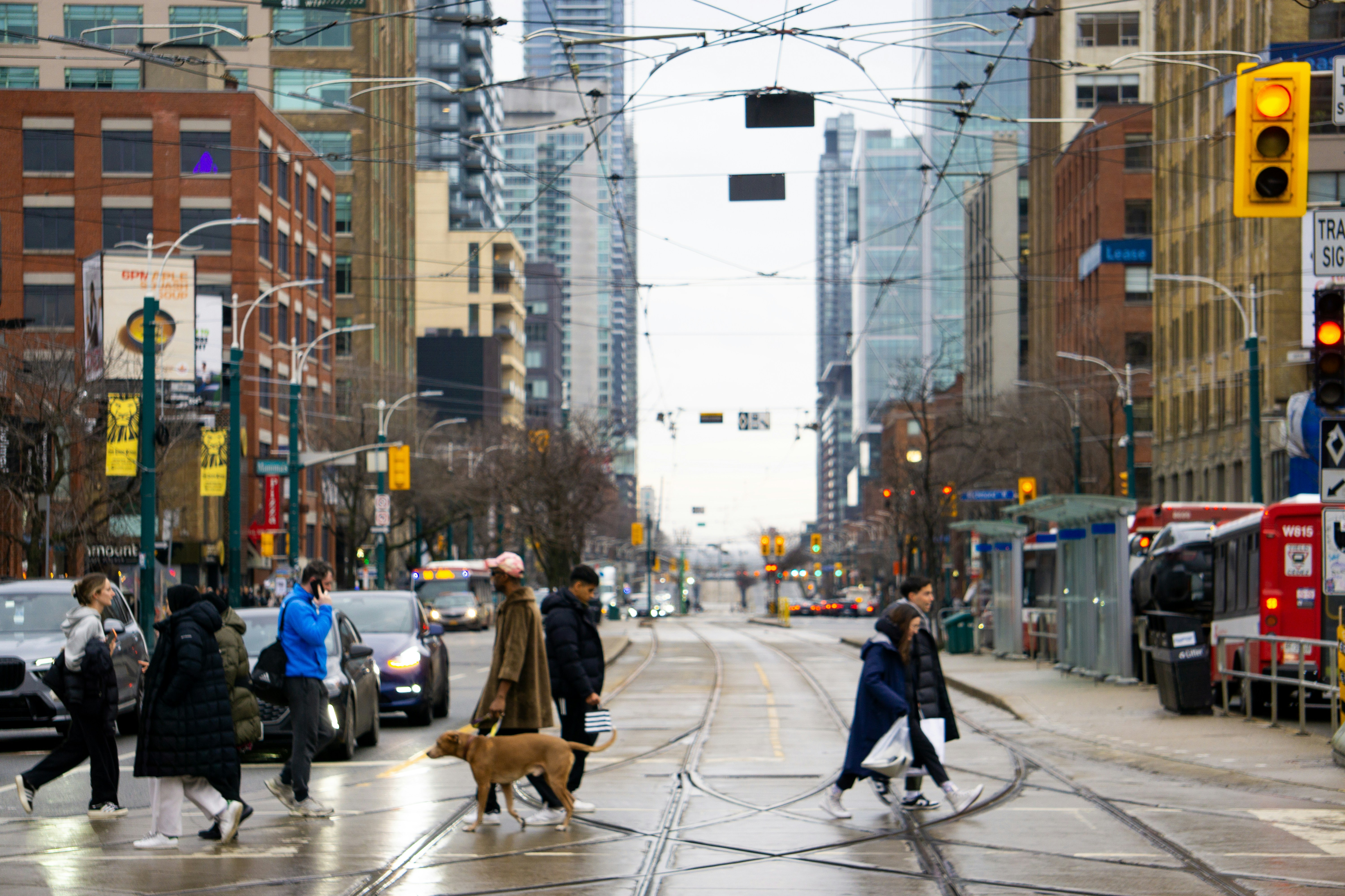 Crosswalk Convergence: City Pulse in Rainy Streetcar Silence