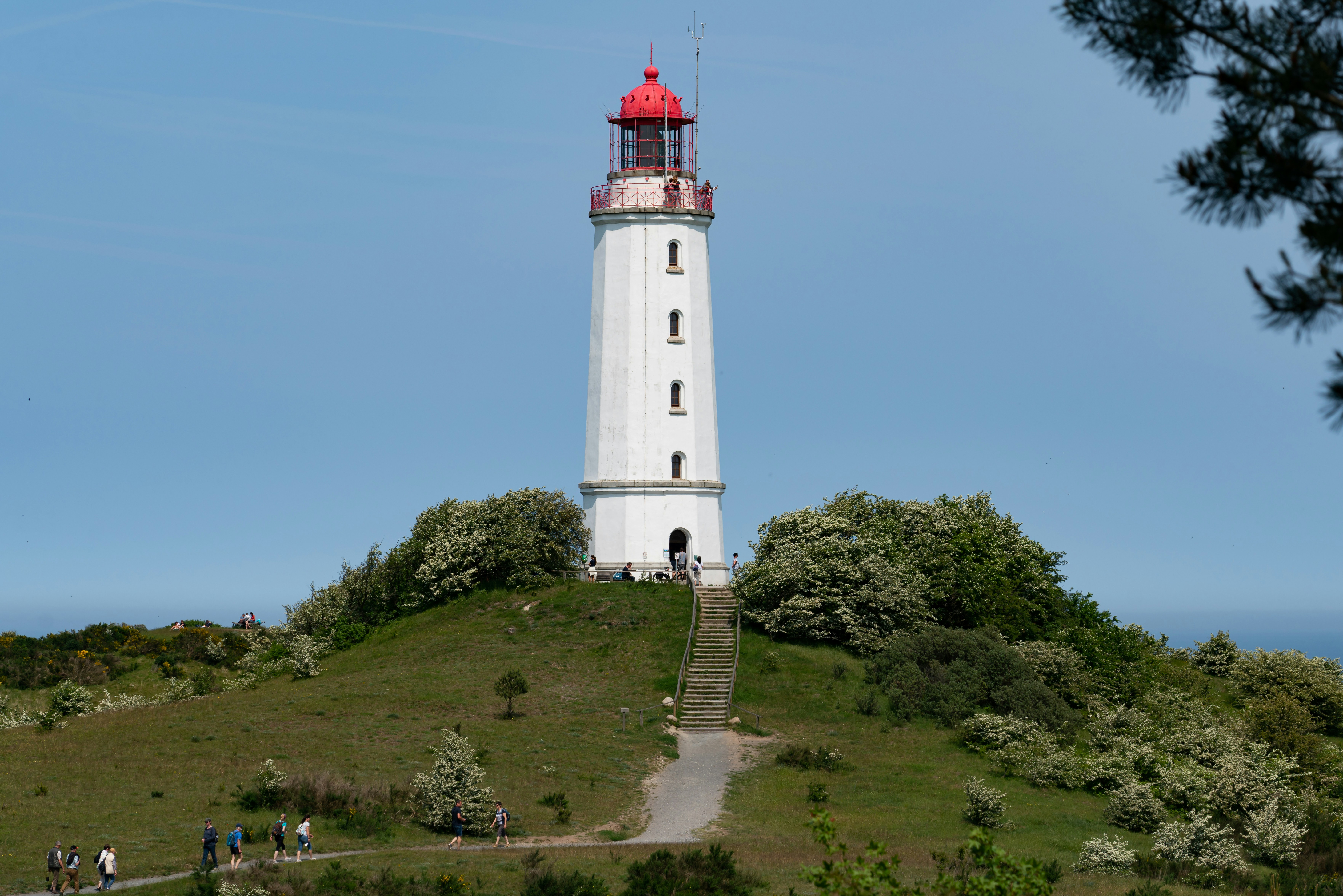 A white and red lighthouse on top of a hill photo – Free Human Image on ...