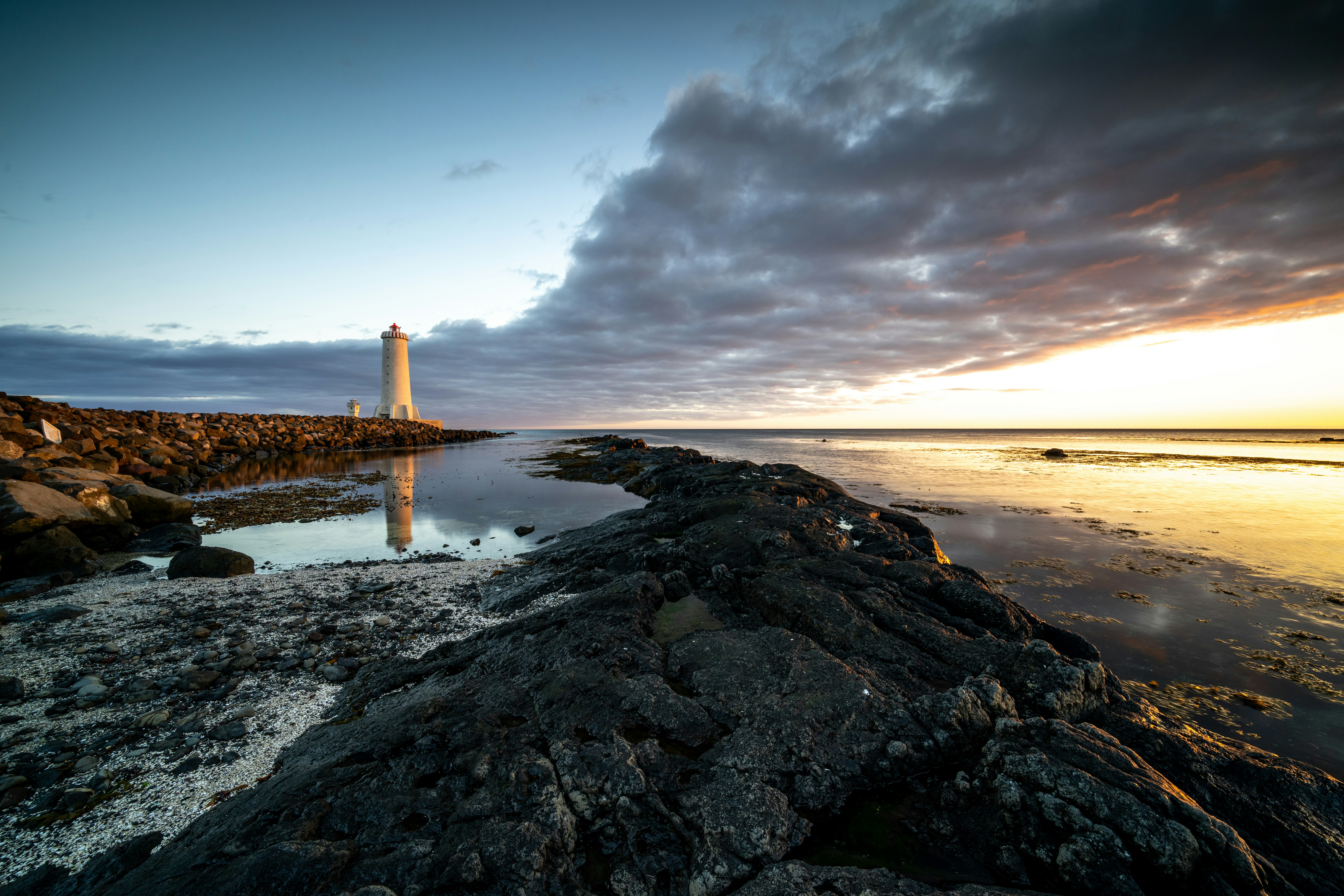 A light house sitting on top of a rocky beach photo – Free Island Image ...