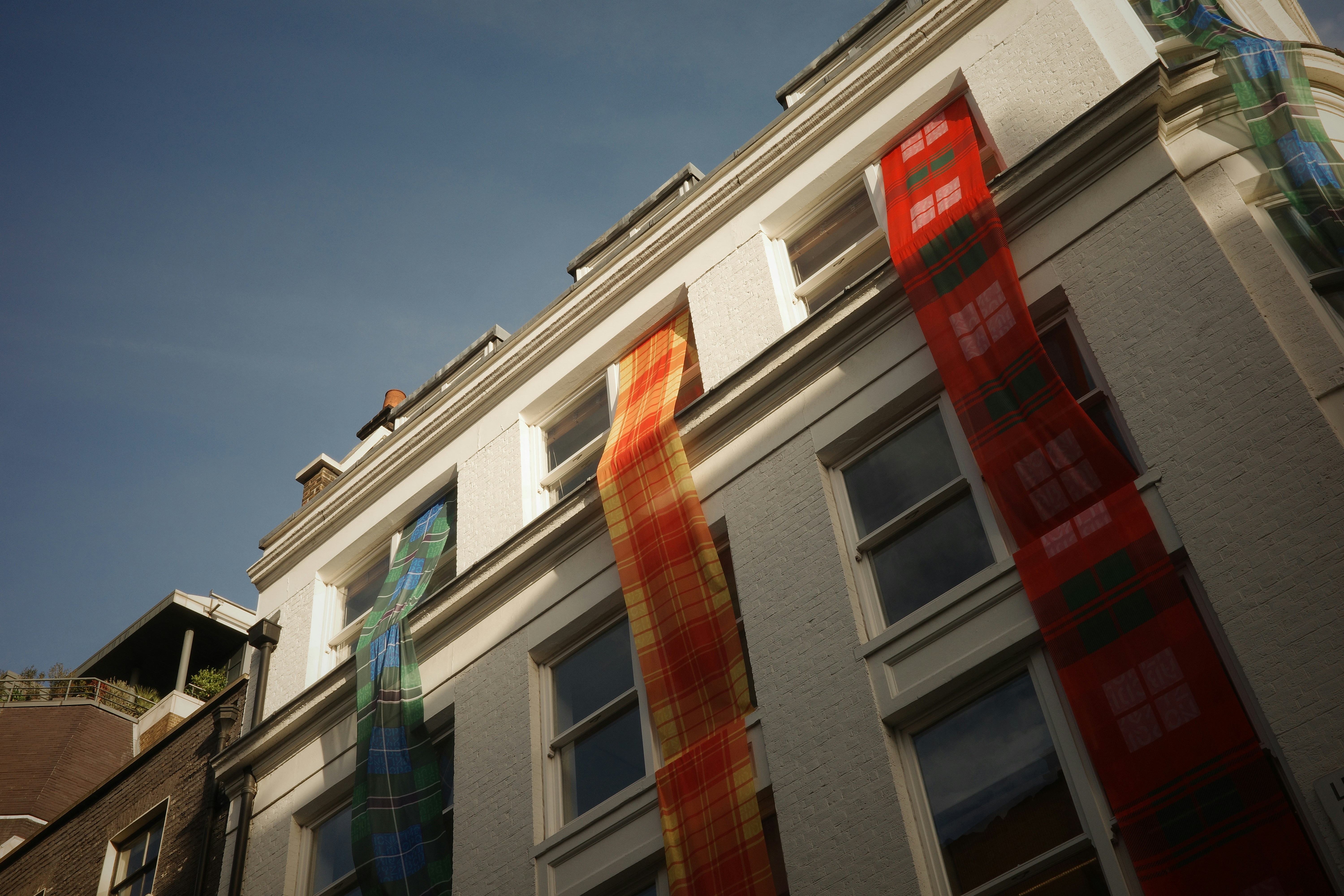 Colorful banners ascending a sunlit facade