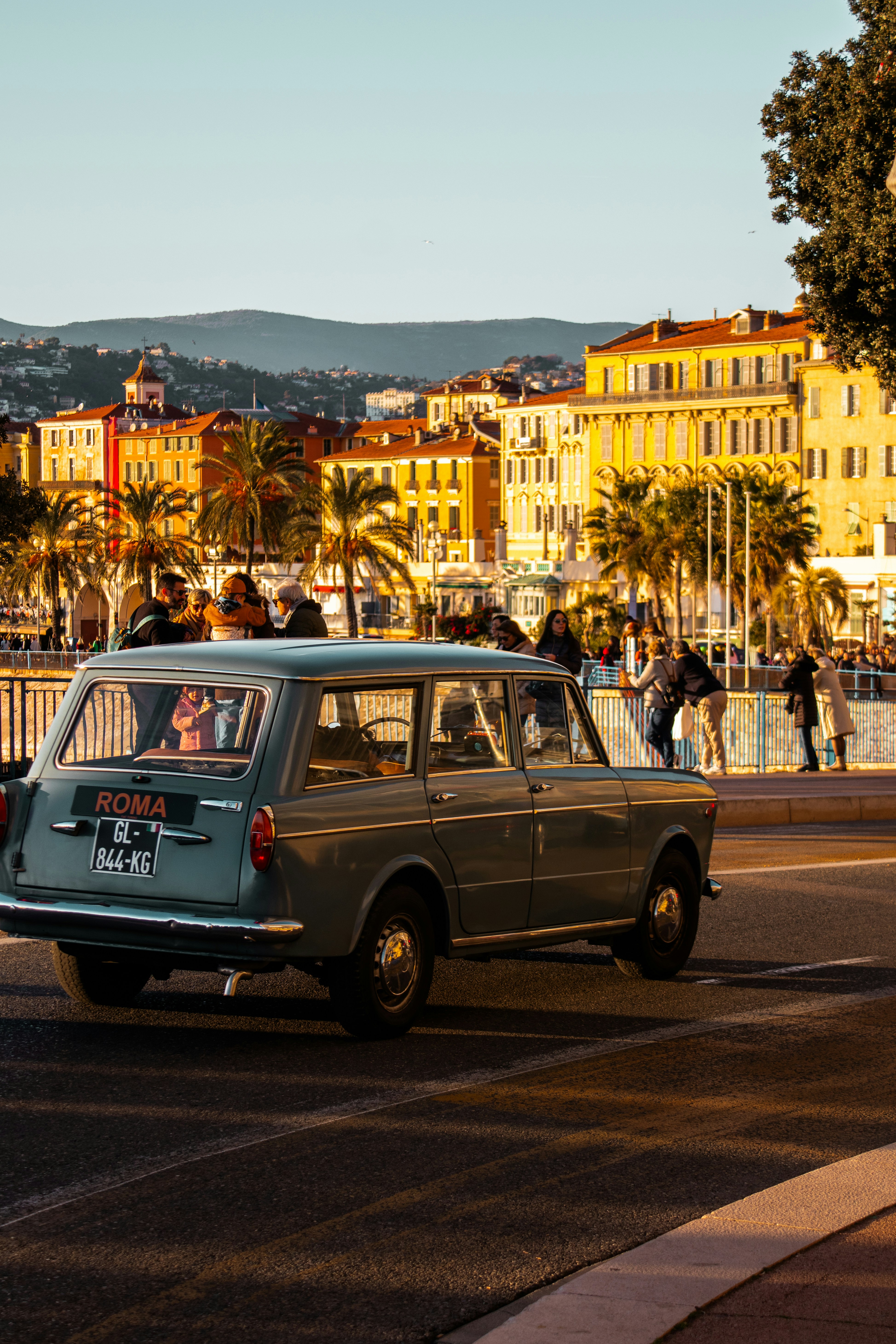 A small car driving down a street next to tall buildings photo – Free ...