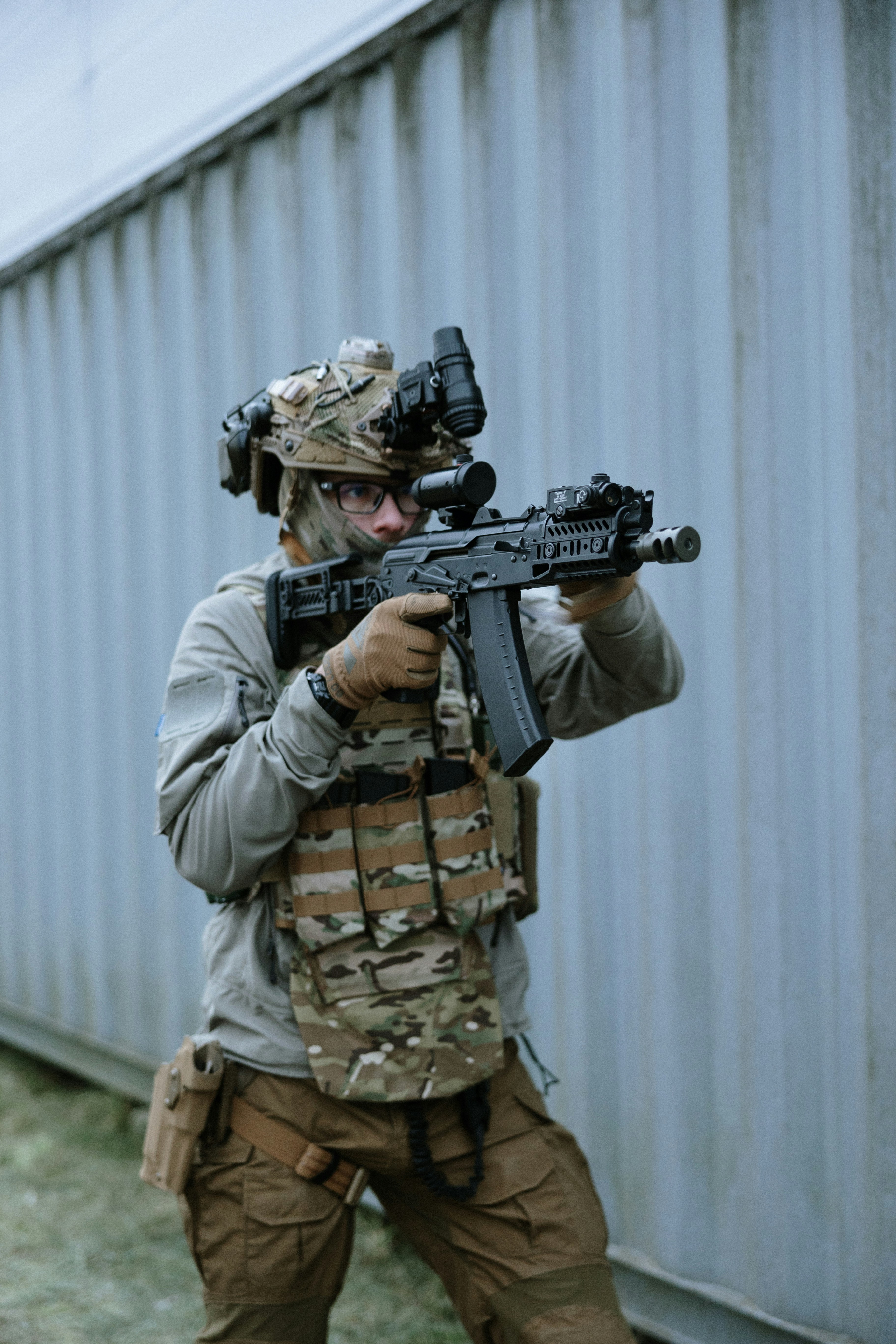 A man holding a rifle while standing next to a building photo – Free ...