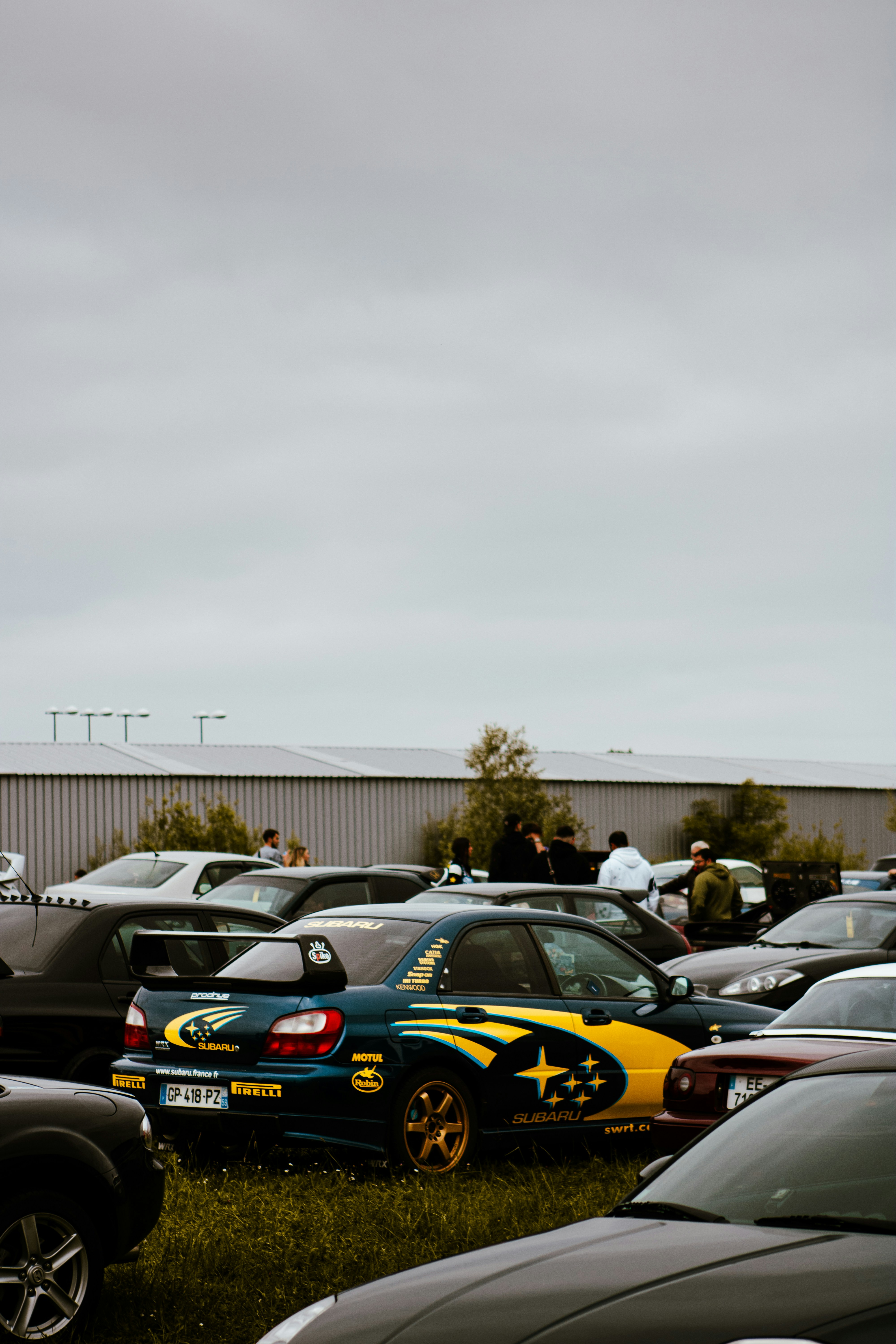 Blue-And-Gold Subaru Rally Car Anchors a Car Meet Under Grey Skies