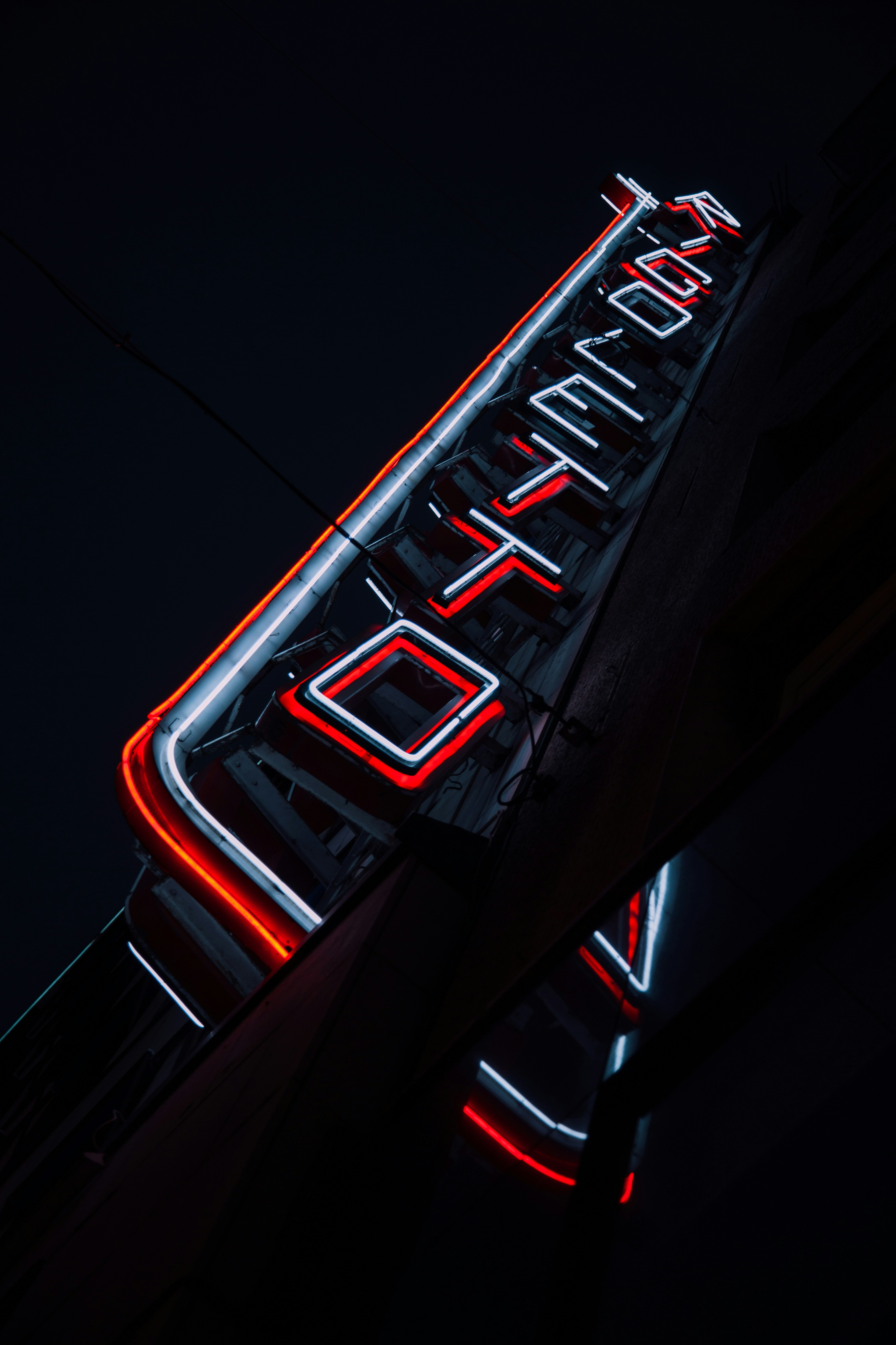 Vibrant neon sign illuminating a dark urban environment, showcasing retro typography in glowing red and blue hues.