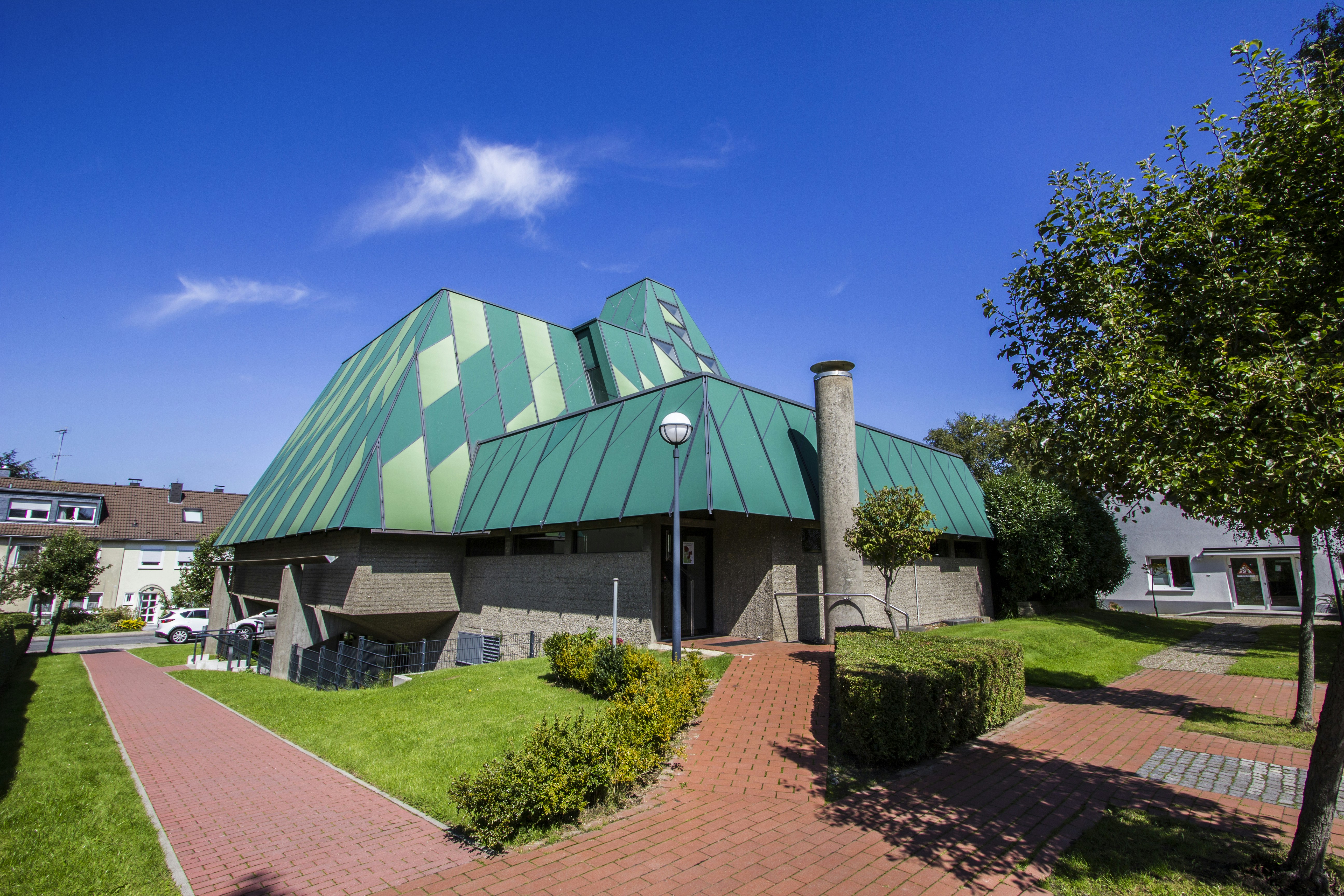 Green Facets over Brick Courtyard: The Geometric Church-like Building