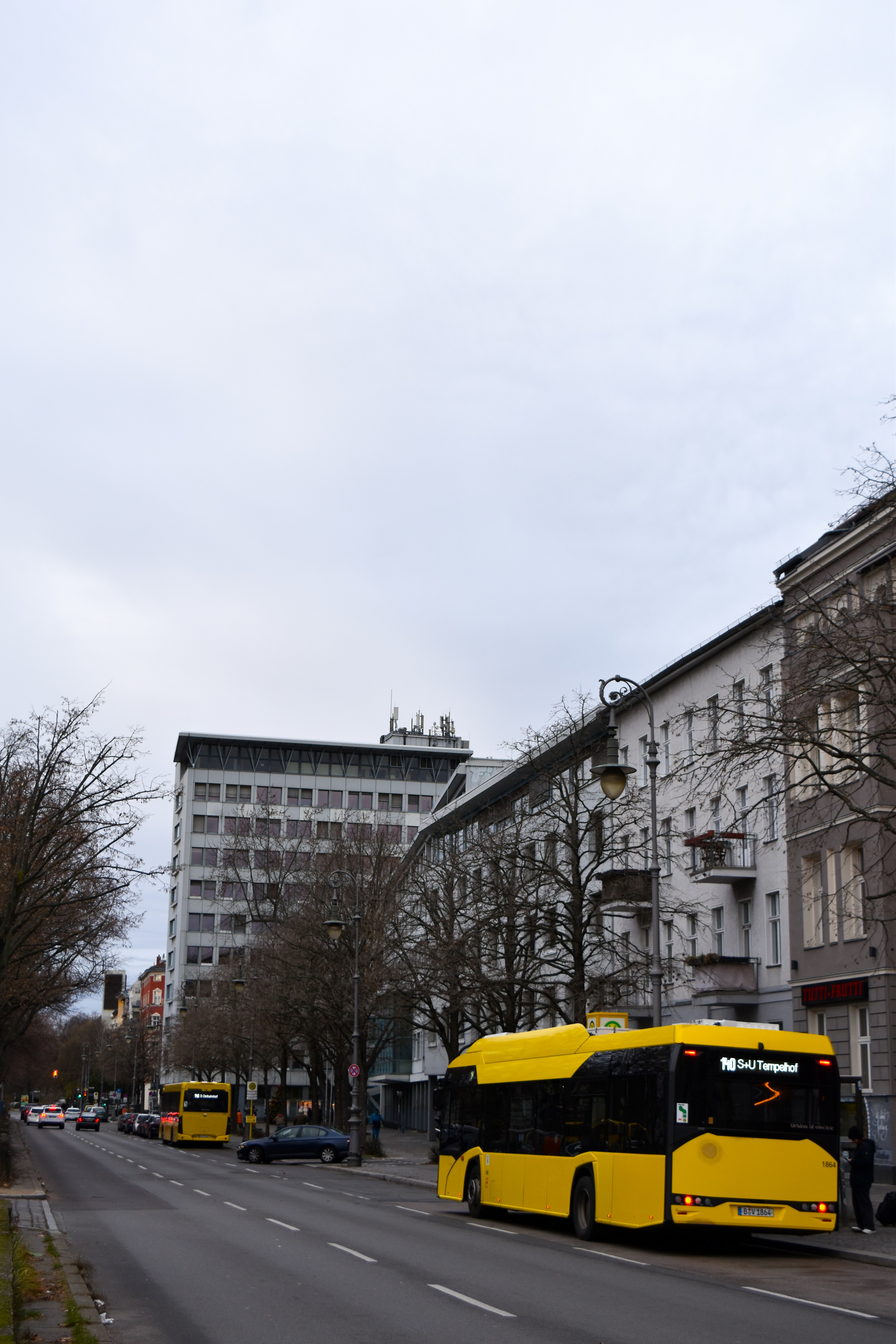 A yellow bus driving down a street next to tall buildings photo – Free ...