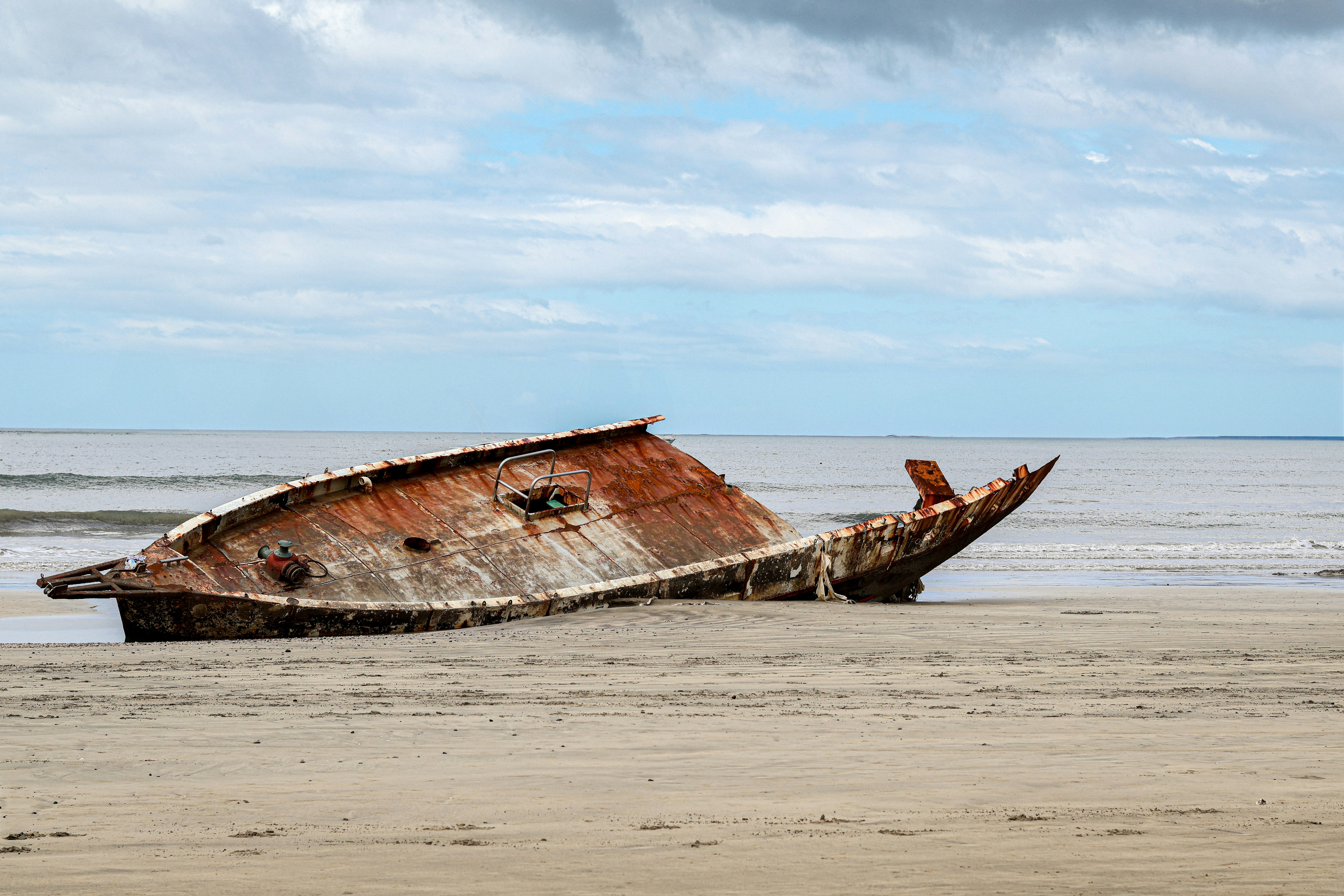 A rusted boat sitting on top of a sandy beach photo – Free Tamarindo ...