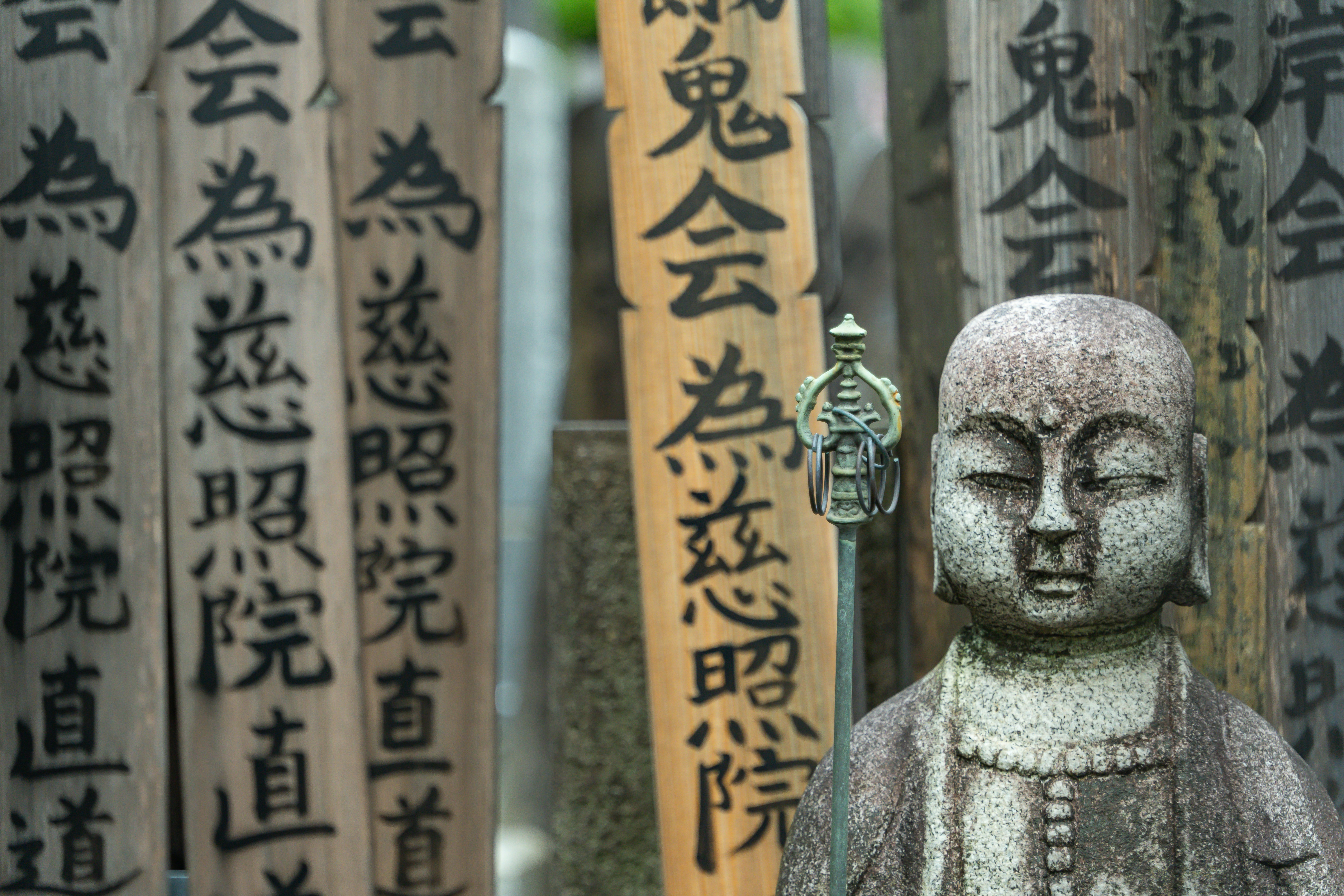 Stone statue of a serene figure surrounded by wooden pillars inscribed with intricate characters.