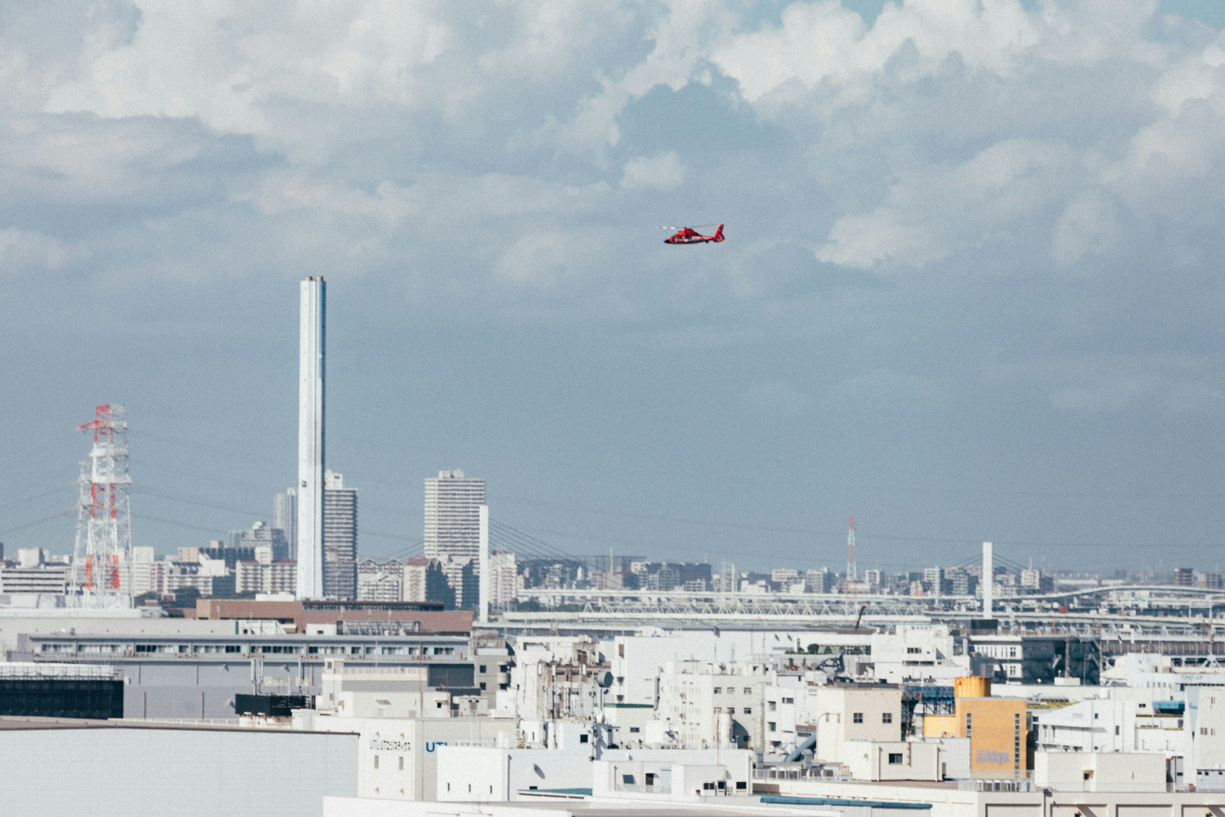 A red plane flying over a city with tall buildings photo – Free Factory ...