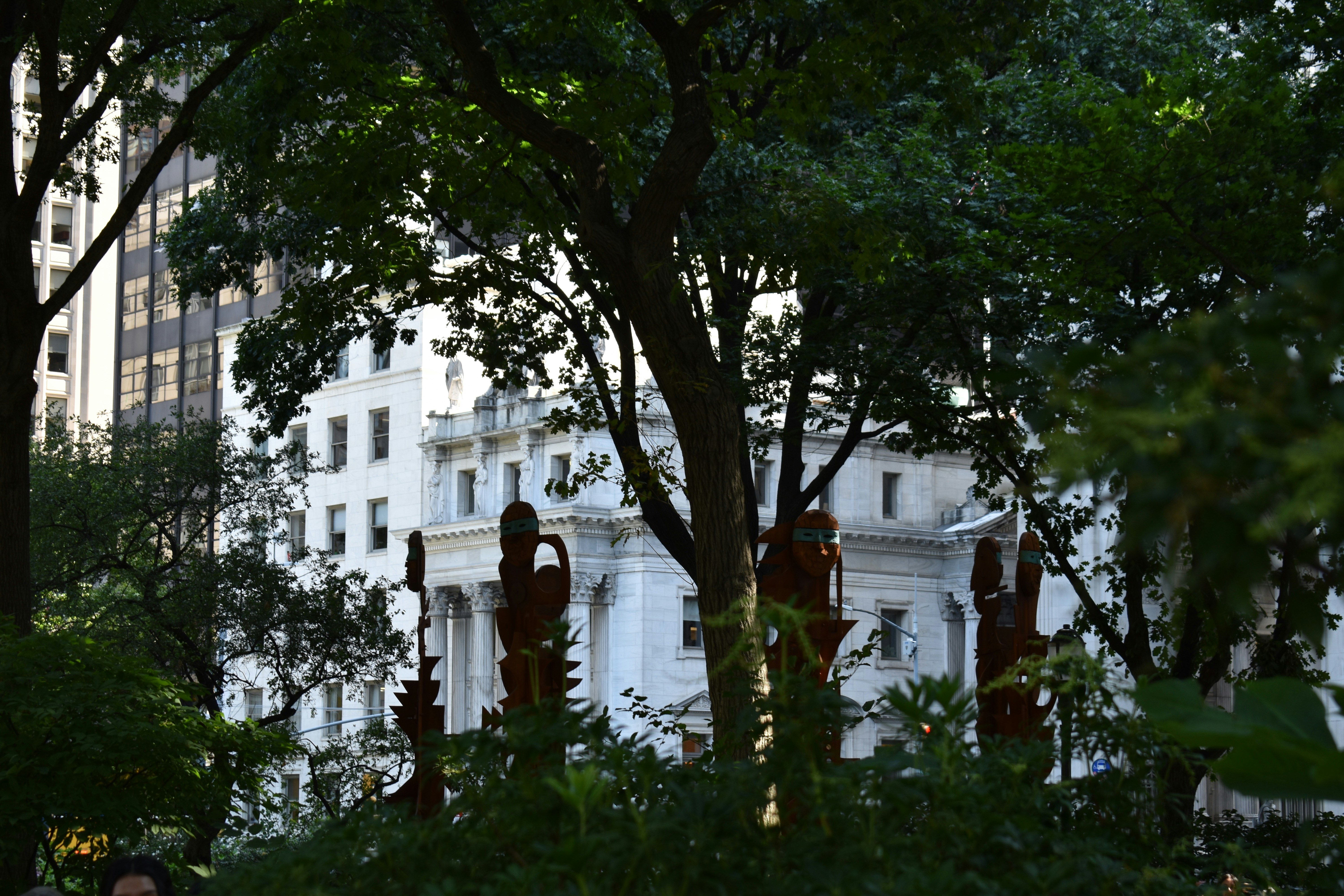Bronze Figures in the Green Veil: A Quiet Ballet of Foliage and Facades