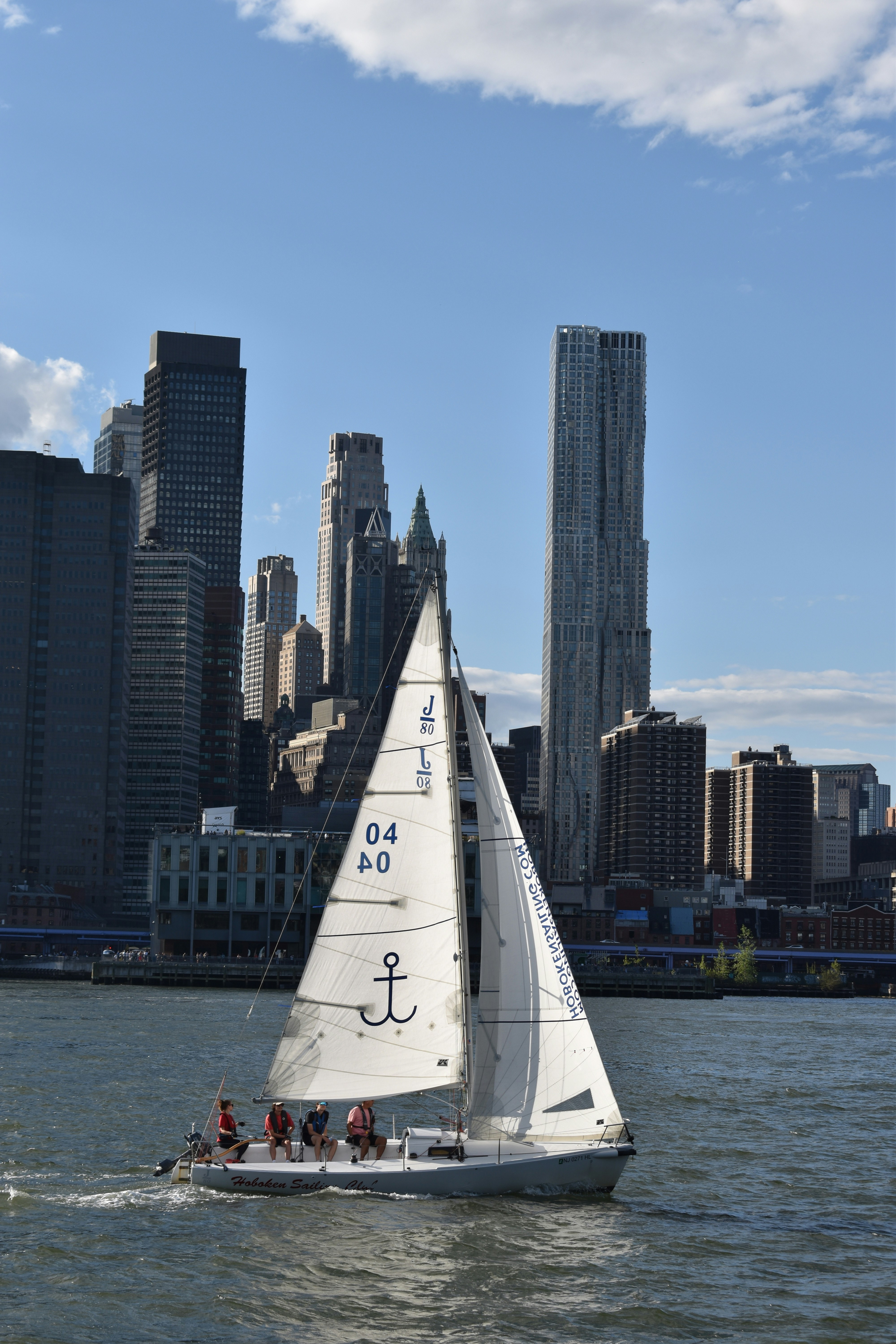 Harbor Sail Beside a Skyline of Steel and Glass