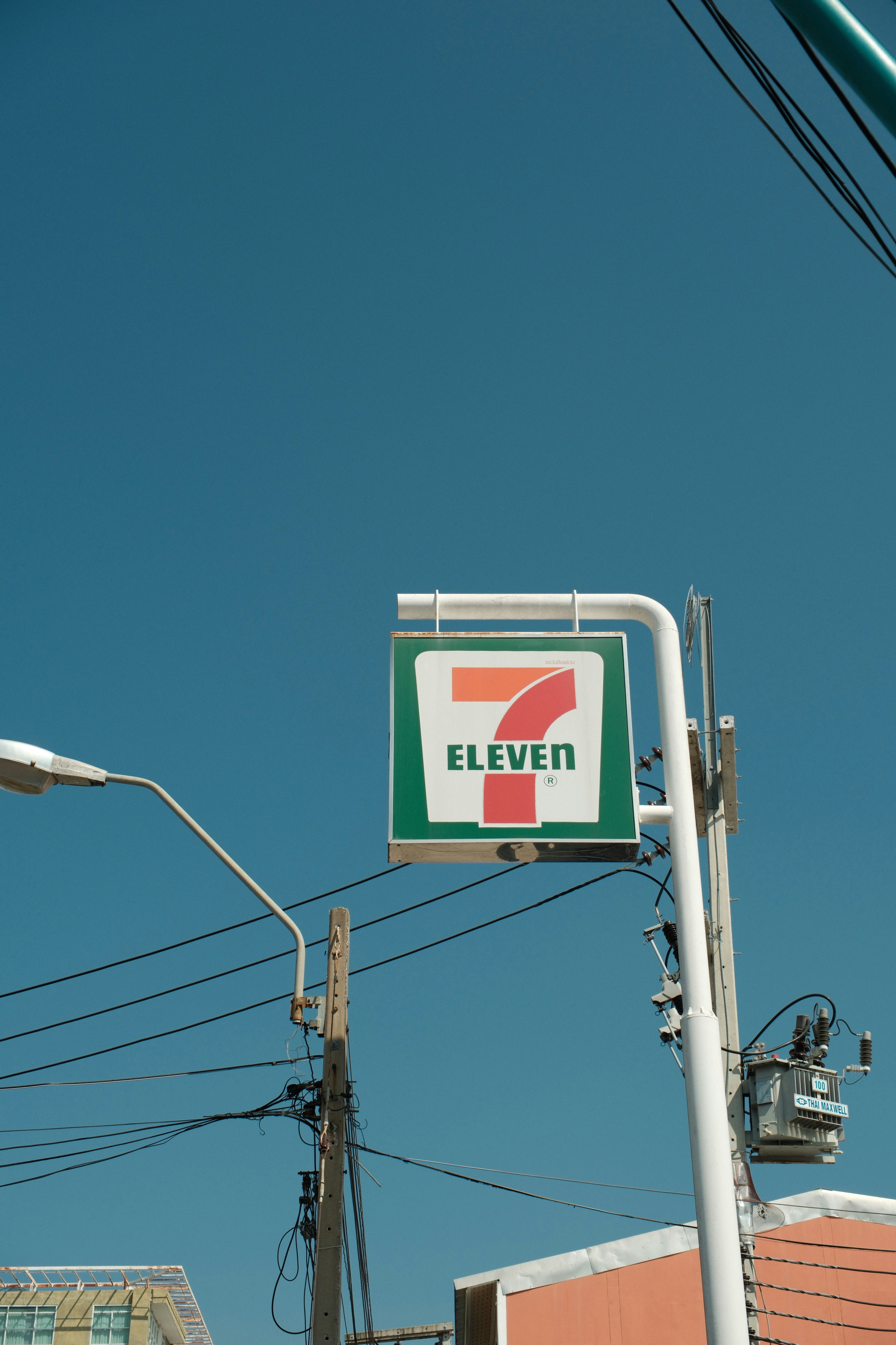 A seven eleven sign hanging off the side of a building photo – Free ...