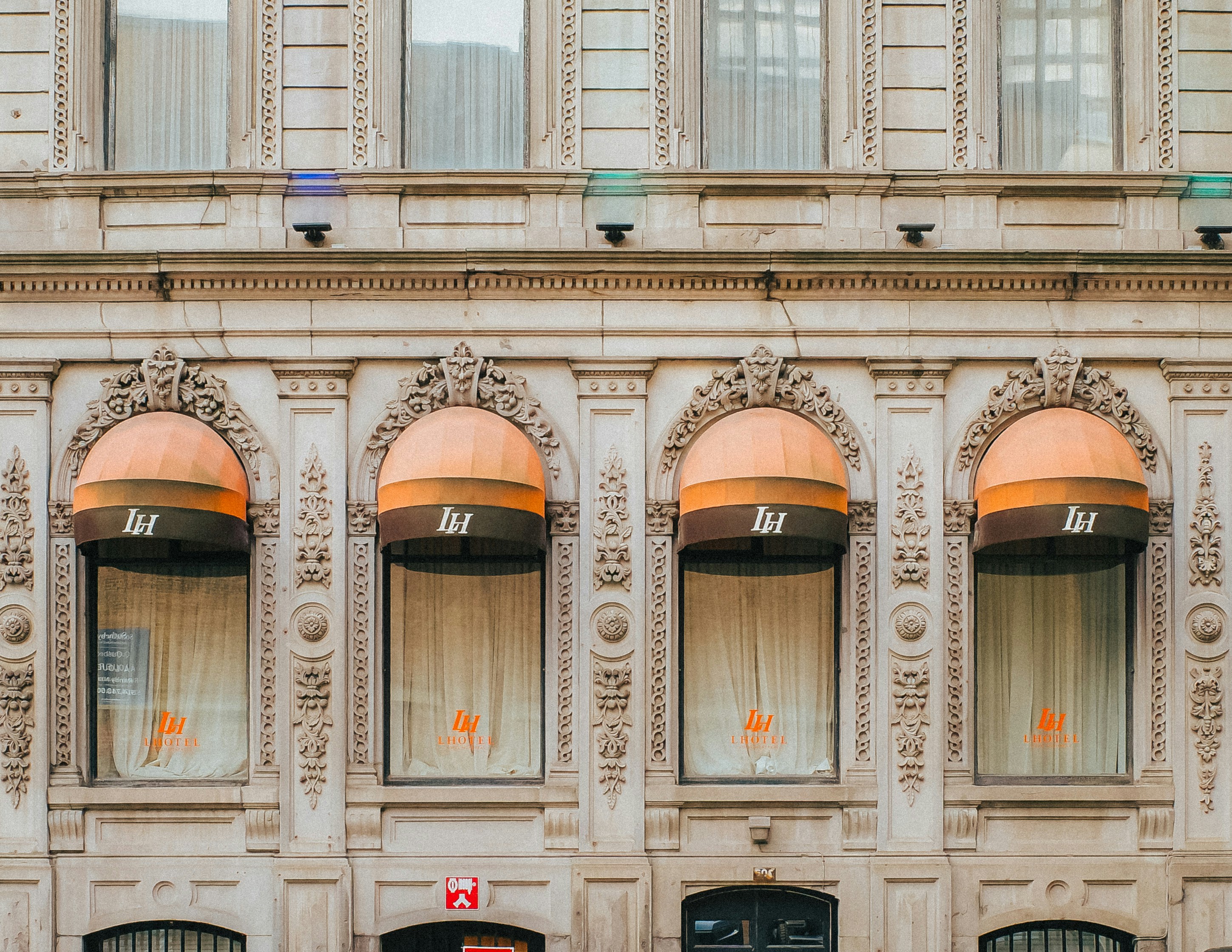 Detailed facade with ornate carvings and orange awnings over tall windows.