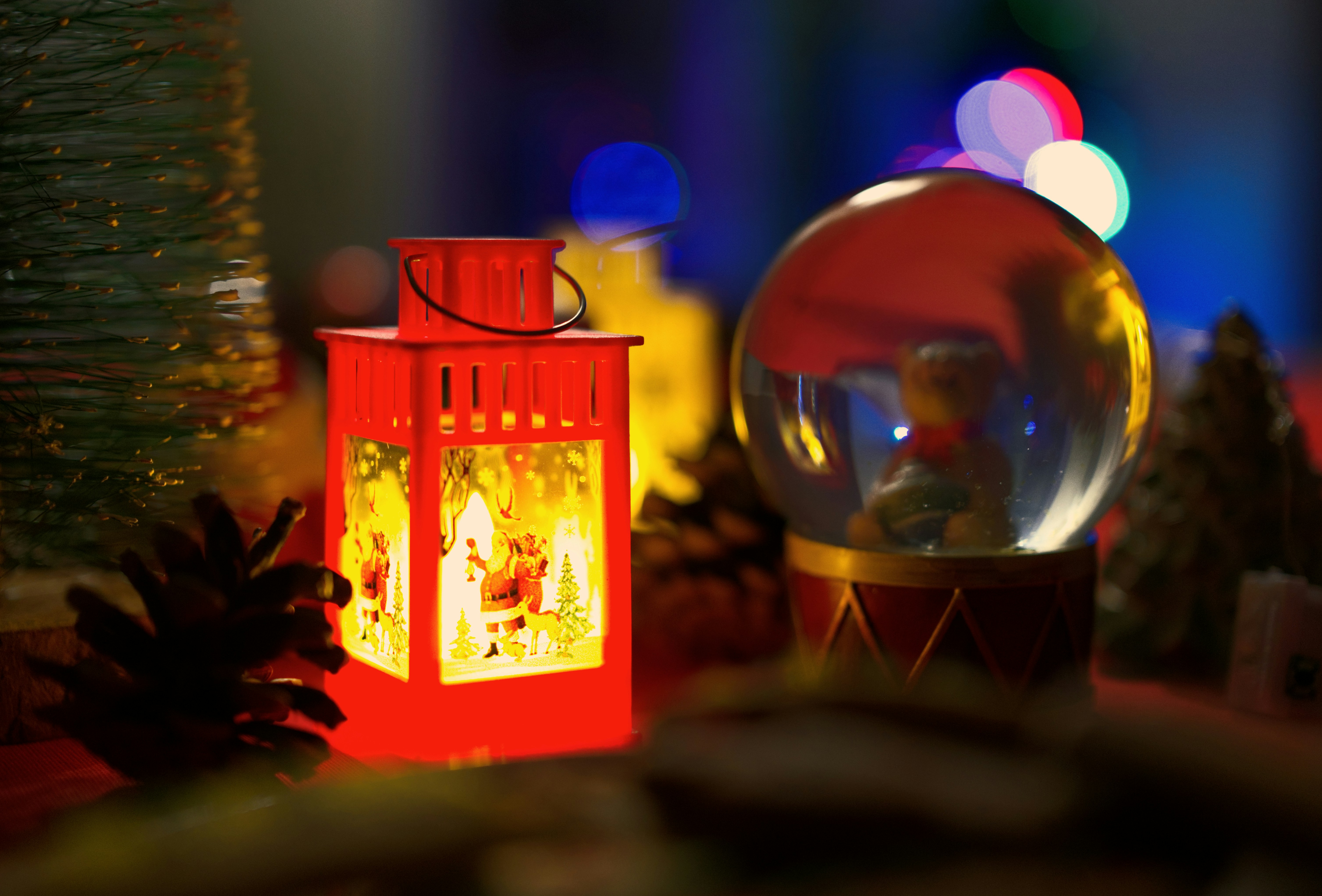 Warm candlelight illuminates a festive scene with a snow globe and colorful bokeh in the background.
