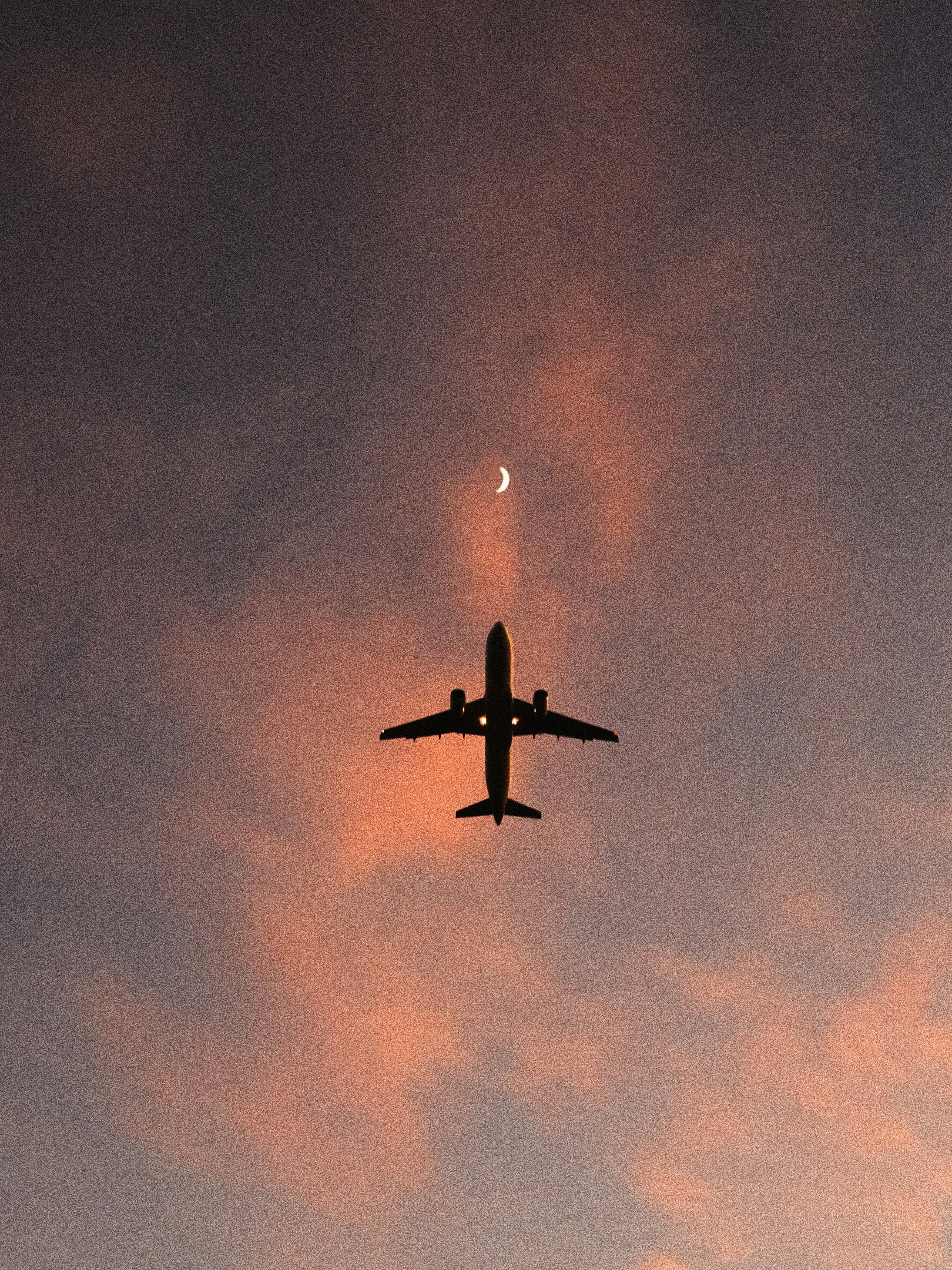 Dusk Silhouette: An Airliner Gliding Under a Crescent Moon