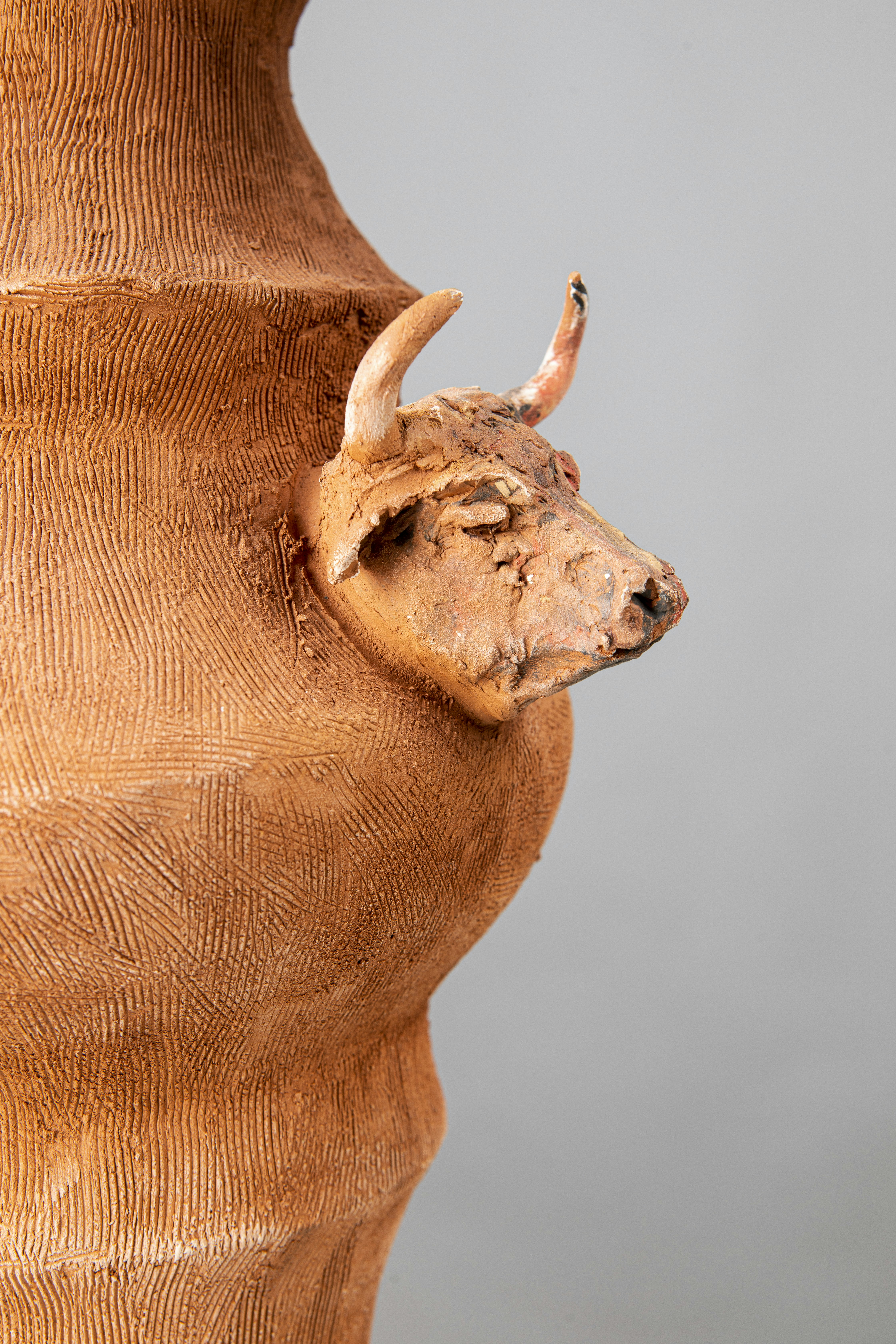 A brown vase with a brown animal head sticking out of it's side