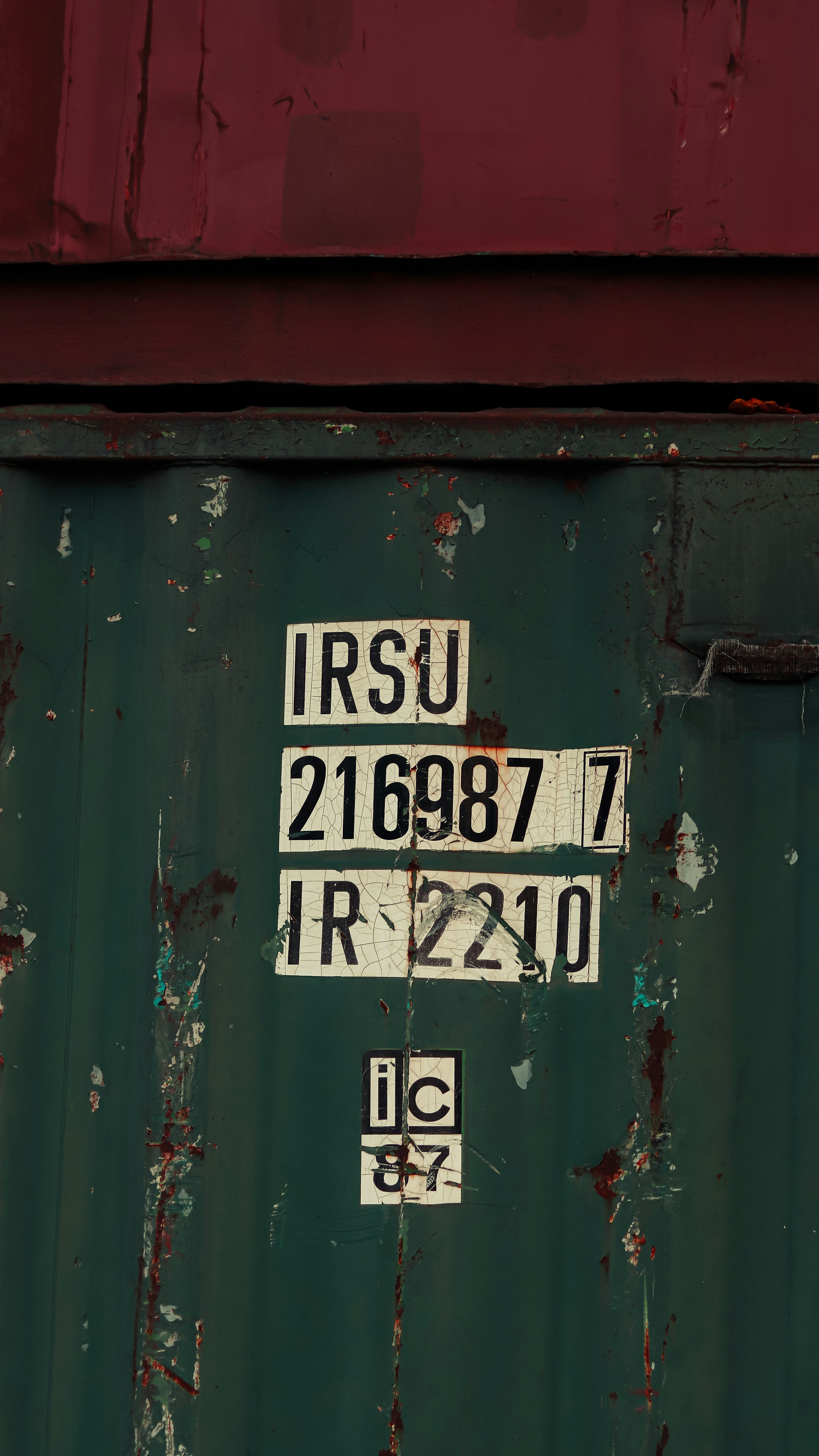 Weathered shipping container displaying faded identification numbers and peeling paint, showcasing the passage of time.