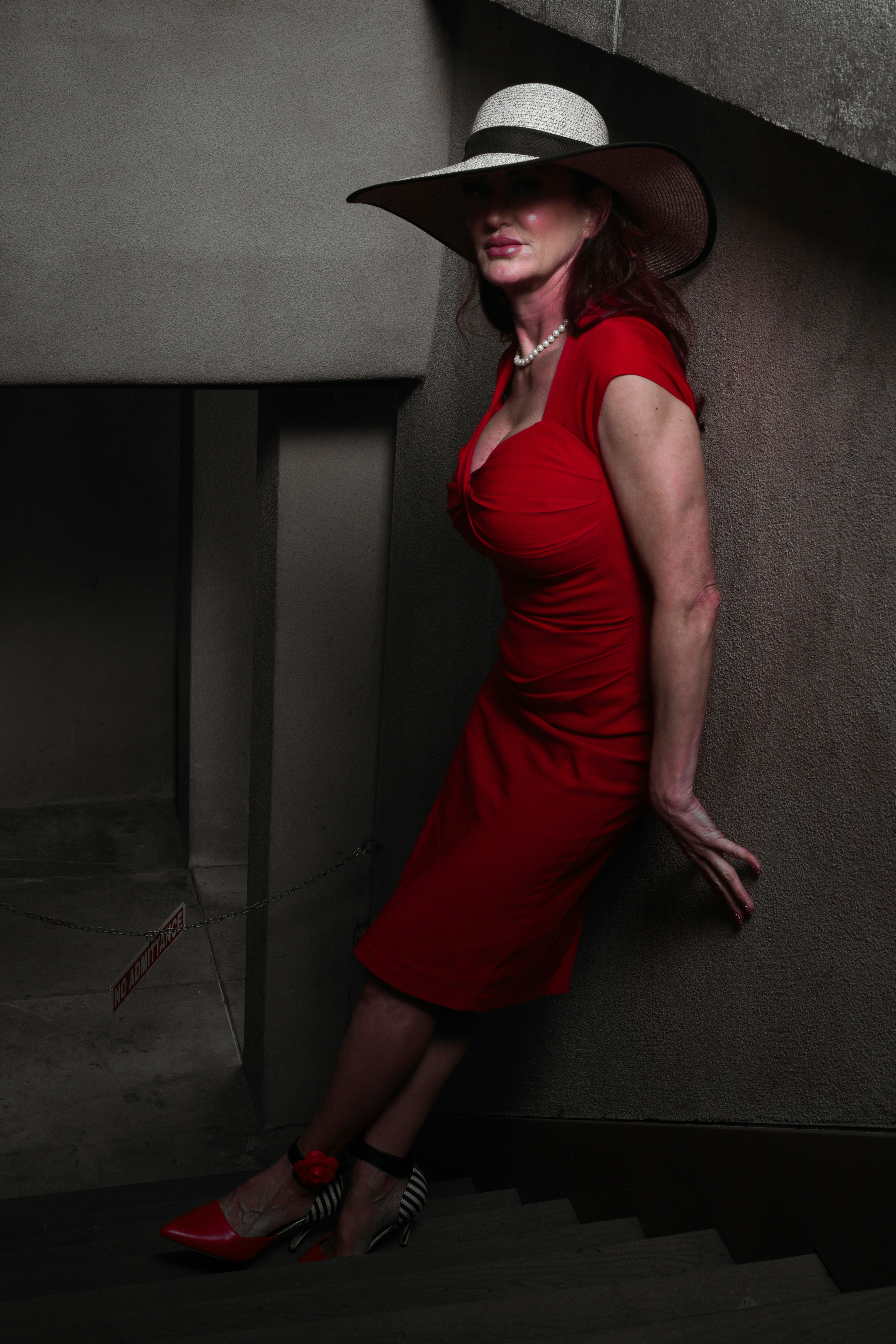 Une femme en robe rouge et chapeau appuyée contre un mur photo – Image ...