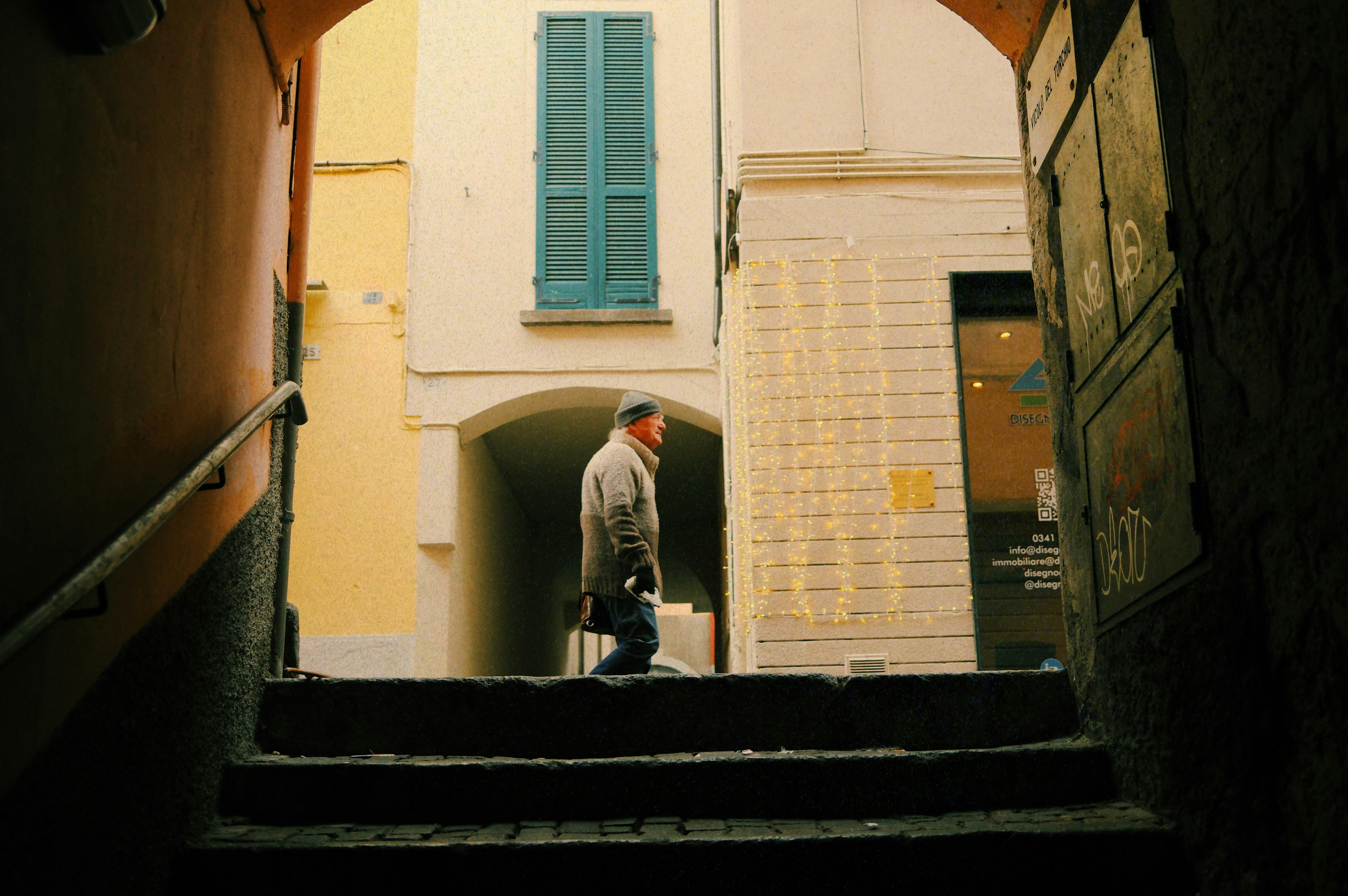 Footpath Sentinel: A Lone Walker Steps Through a Quiet Courtyard
