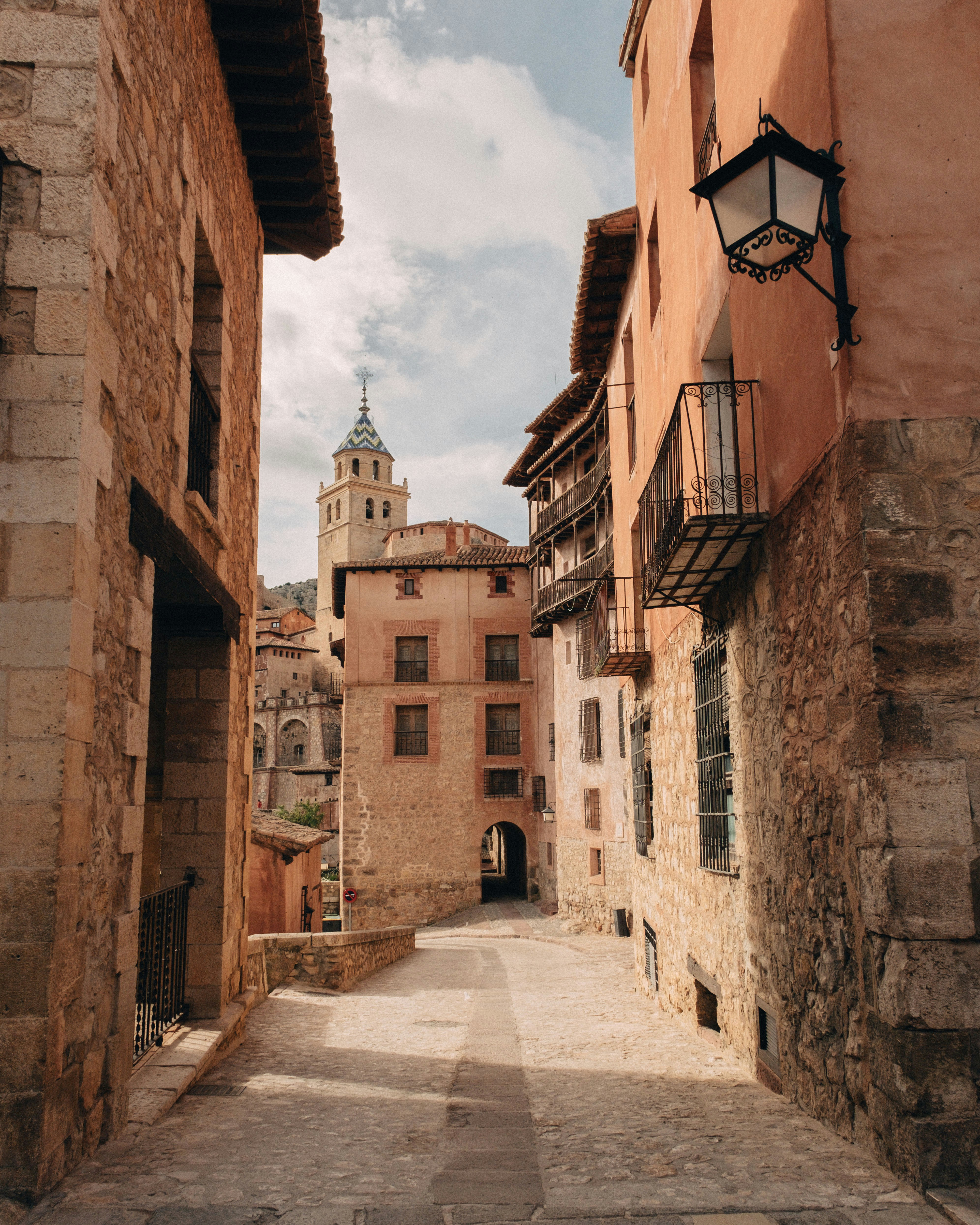 A narrow street with a clock tower in the distance photo – Free ...