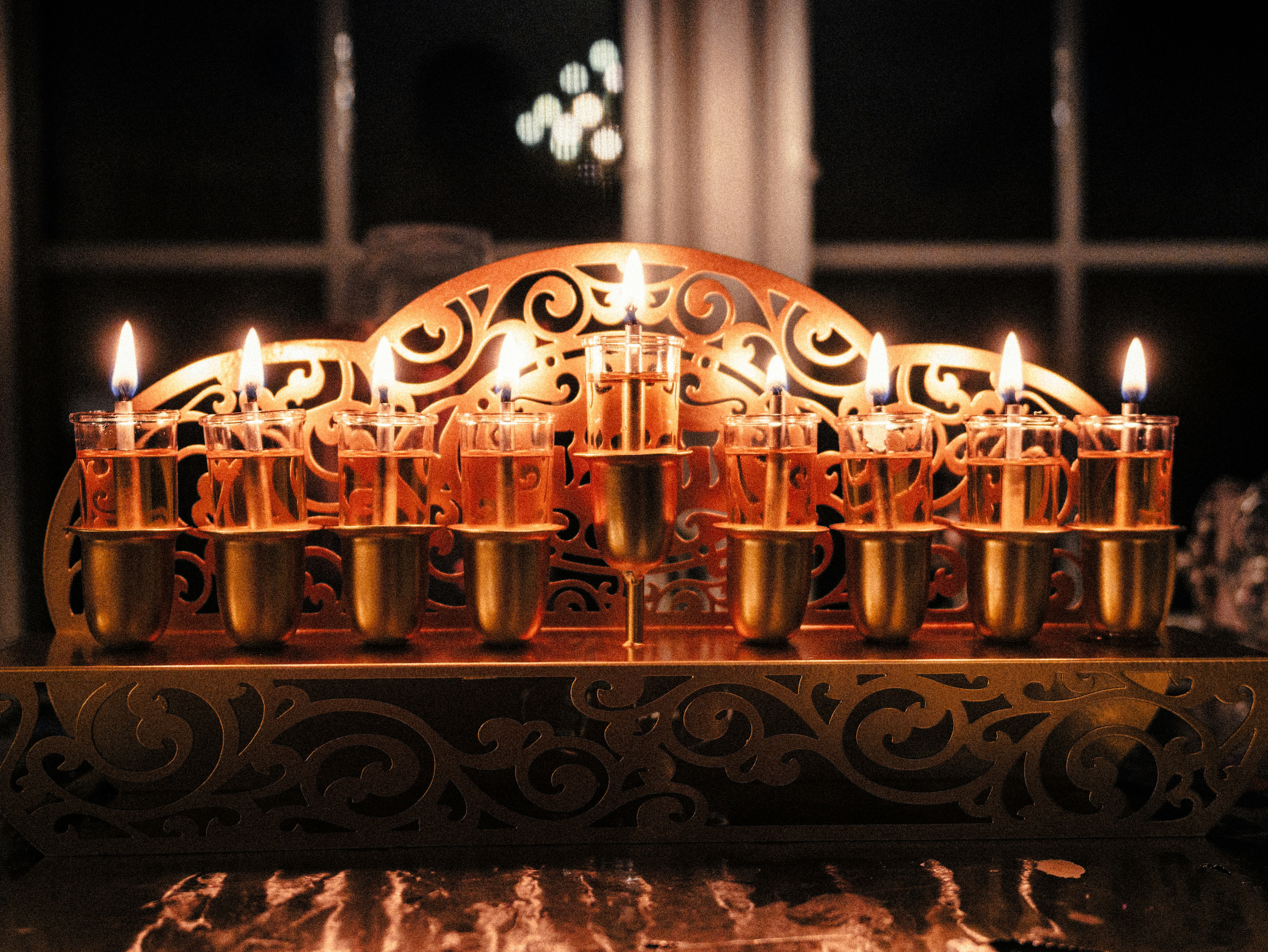 Flame and Filigree: A Row of Brass Candles in Candlelight