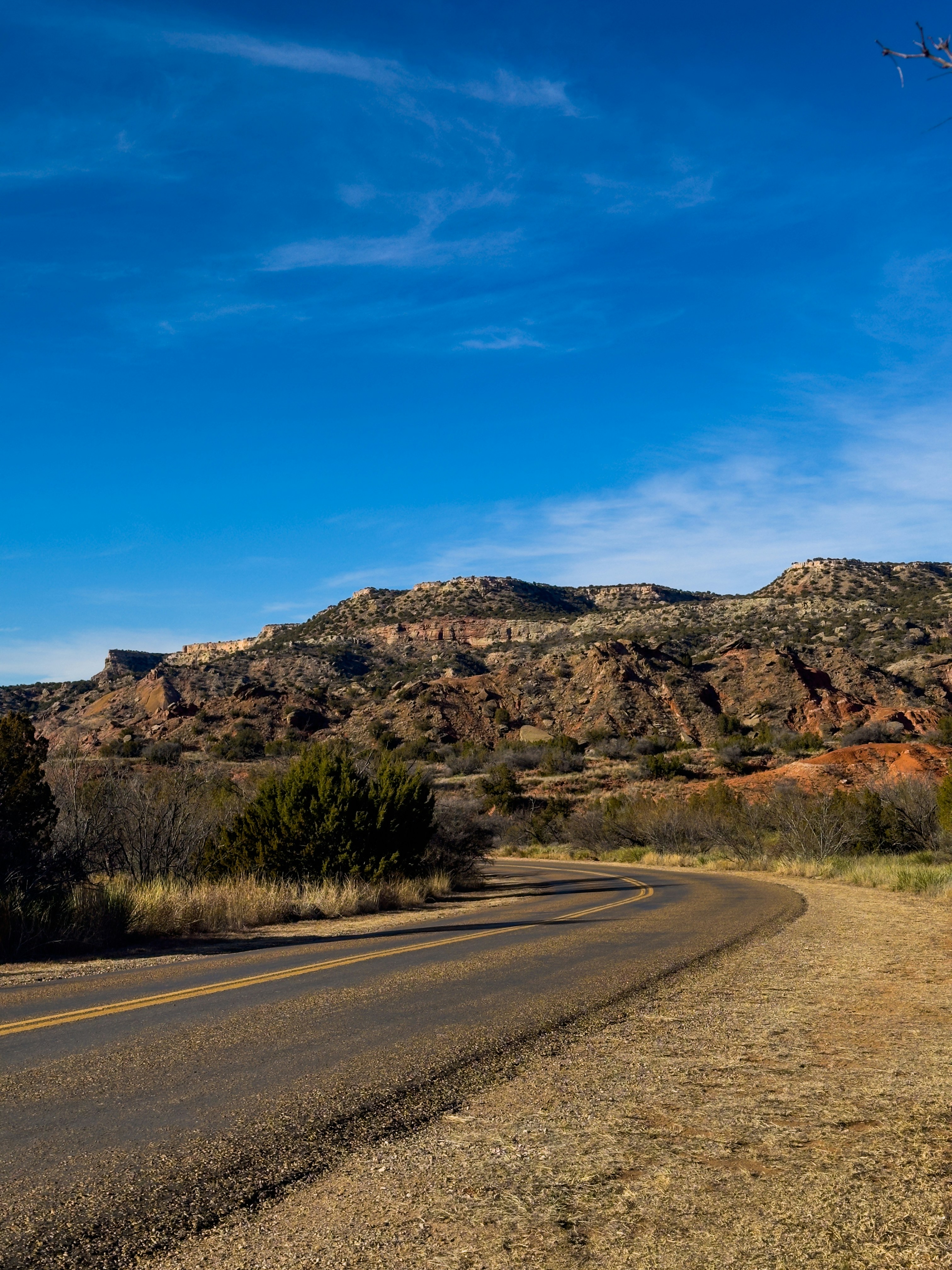 Winding road leading through rocky hills under a clear blue sky.