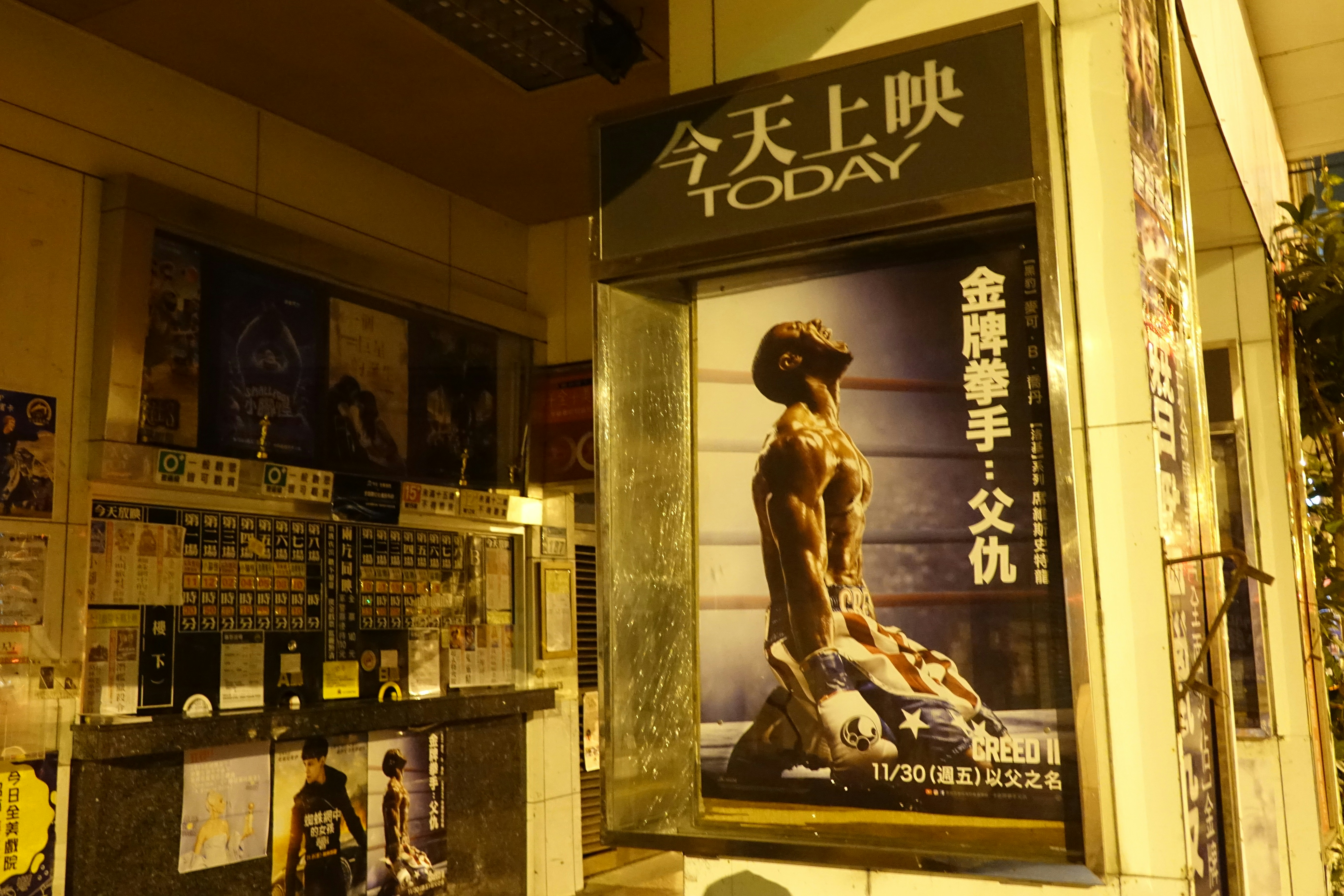 Illuminated theater entrance with a large movie poster depicting a stylized figure.