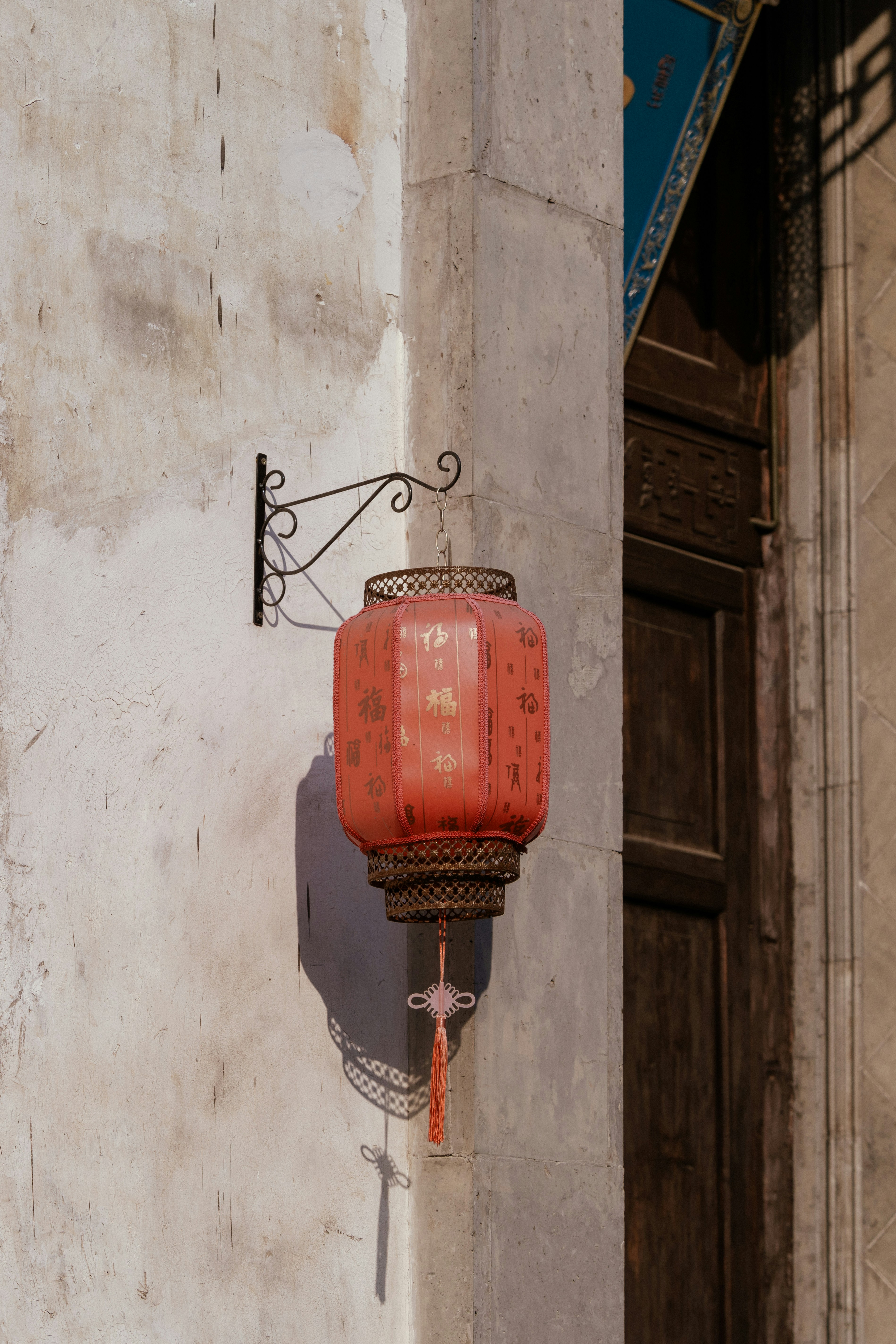Crimson Lantern Adorning a Sunlit Stone Facade