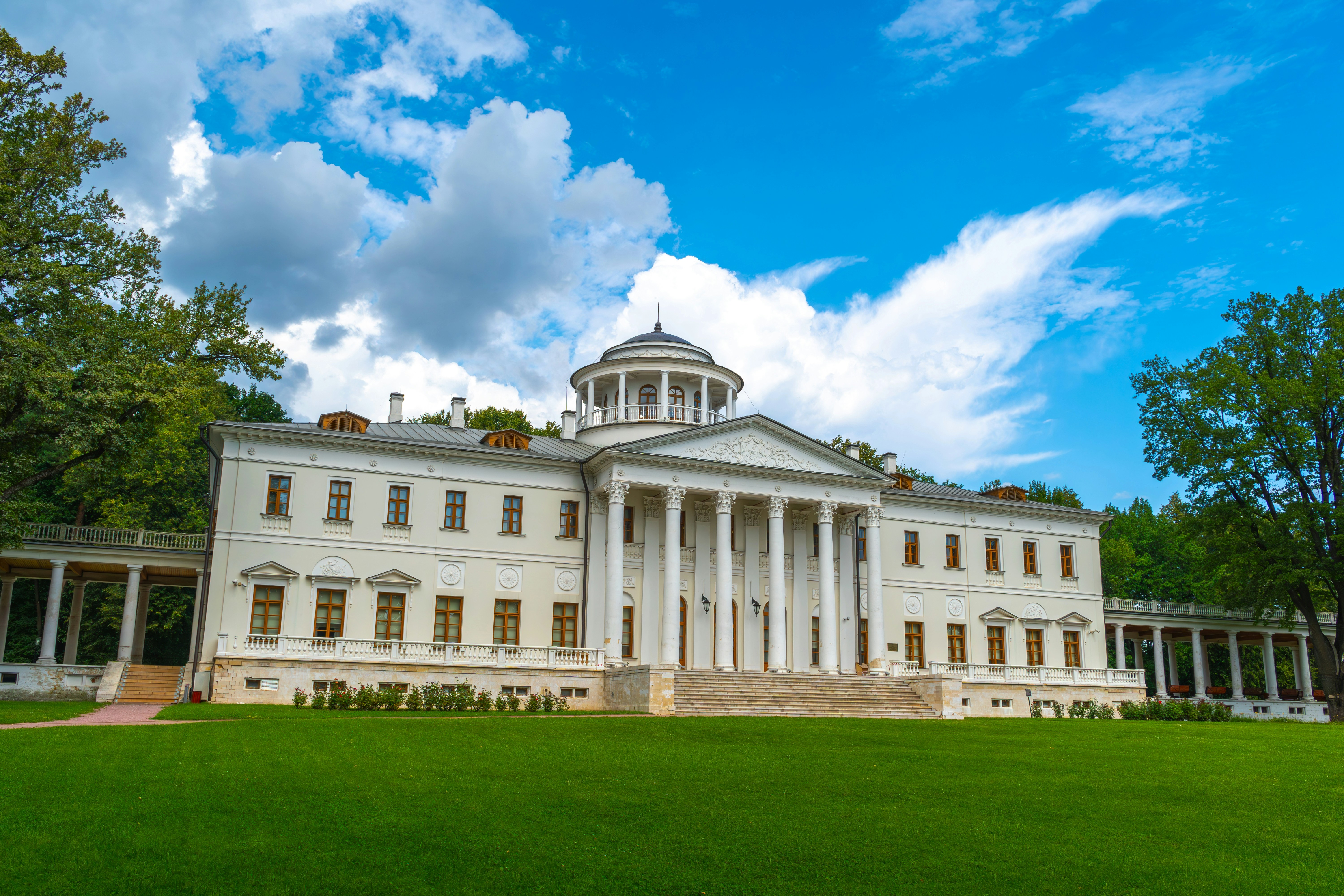 A large white building sitting on top of a lush green field photo ...