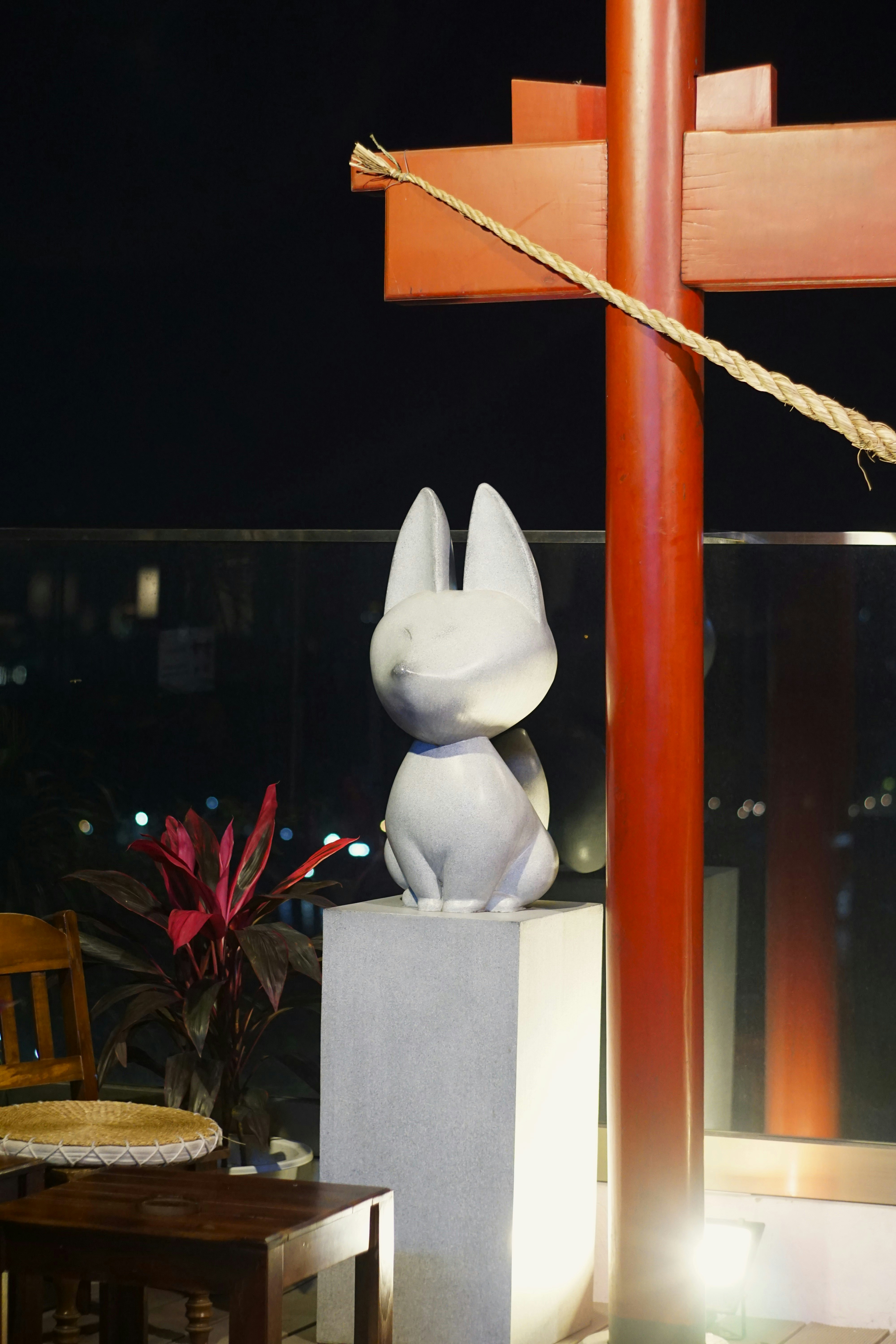 Porcelain Bunny Under a Crimson Beam: Night Interior Sculpture