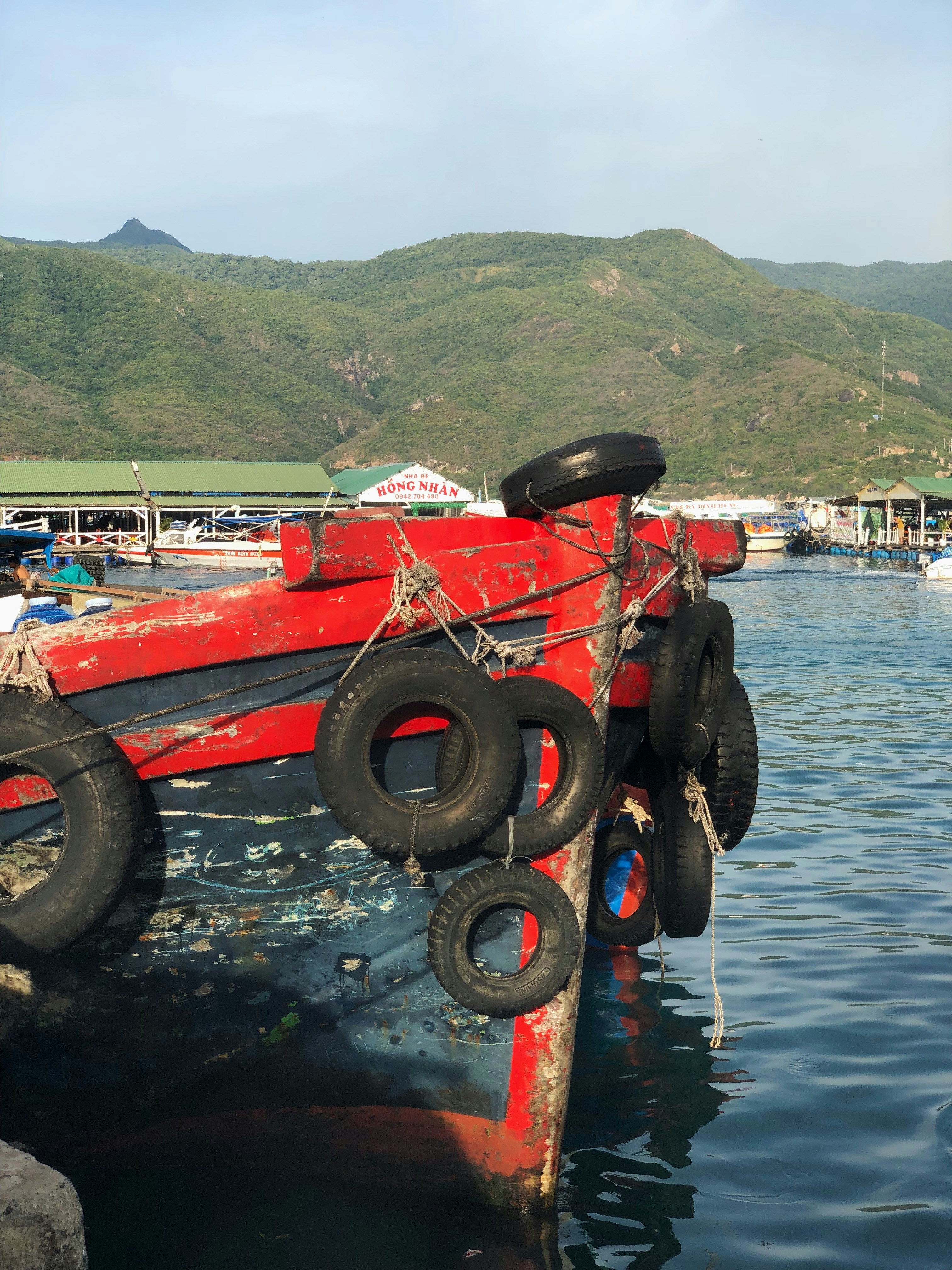 Red-Tiled Bow of the Harbor: Tires, Water, and Mountain Backdrop