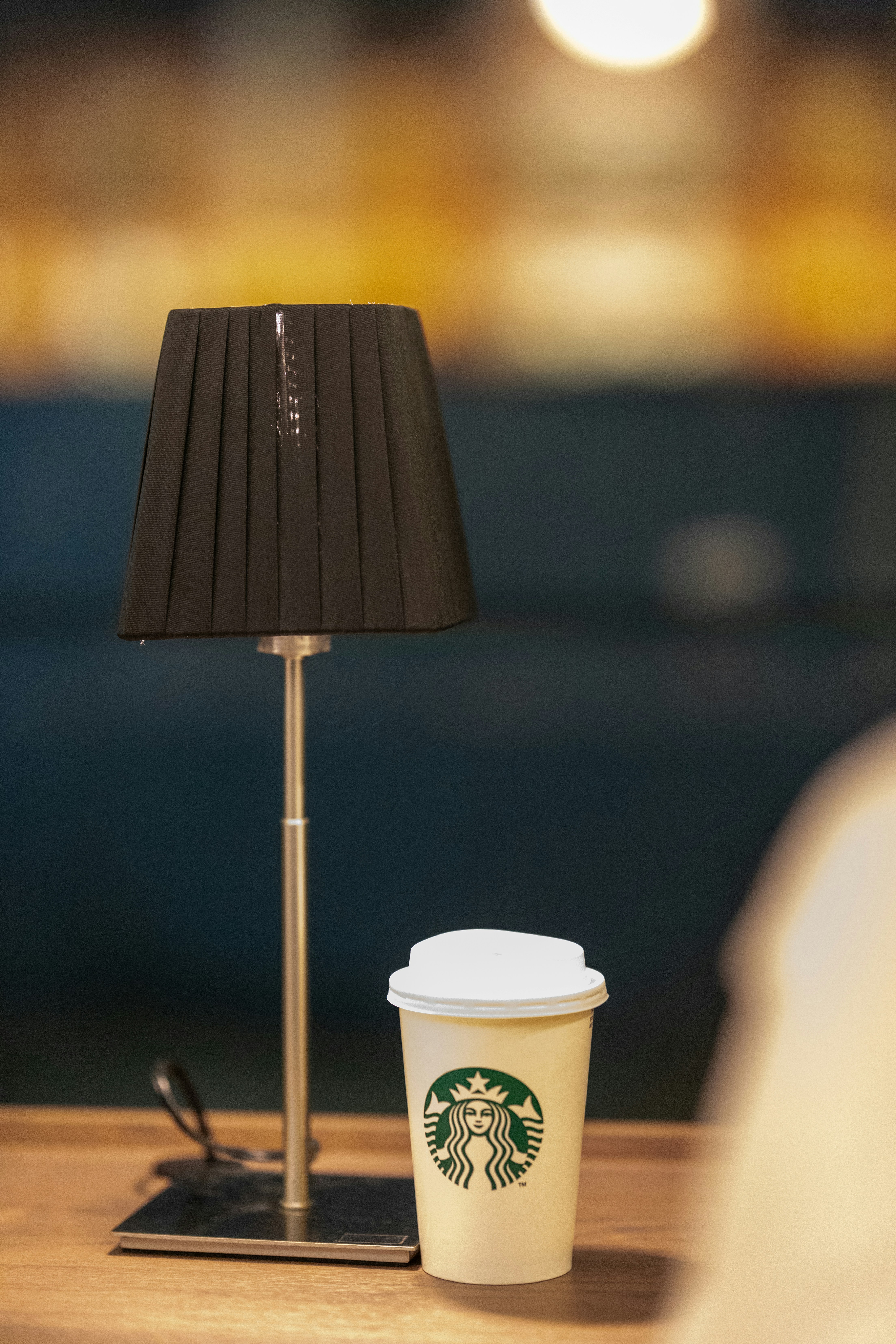 Minimal Lounge Glow: A Lamp and Starbucks Cup in Soft Bar Lighting