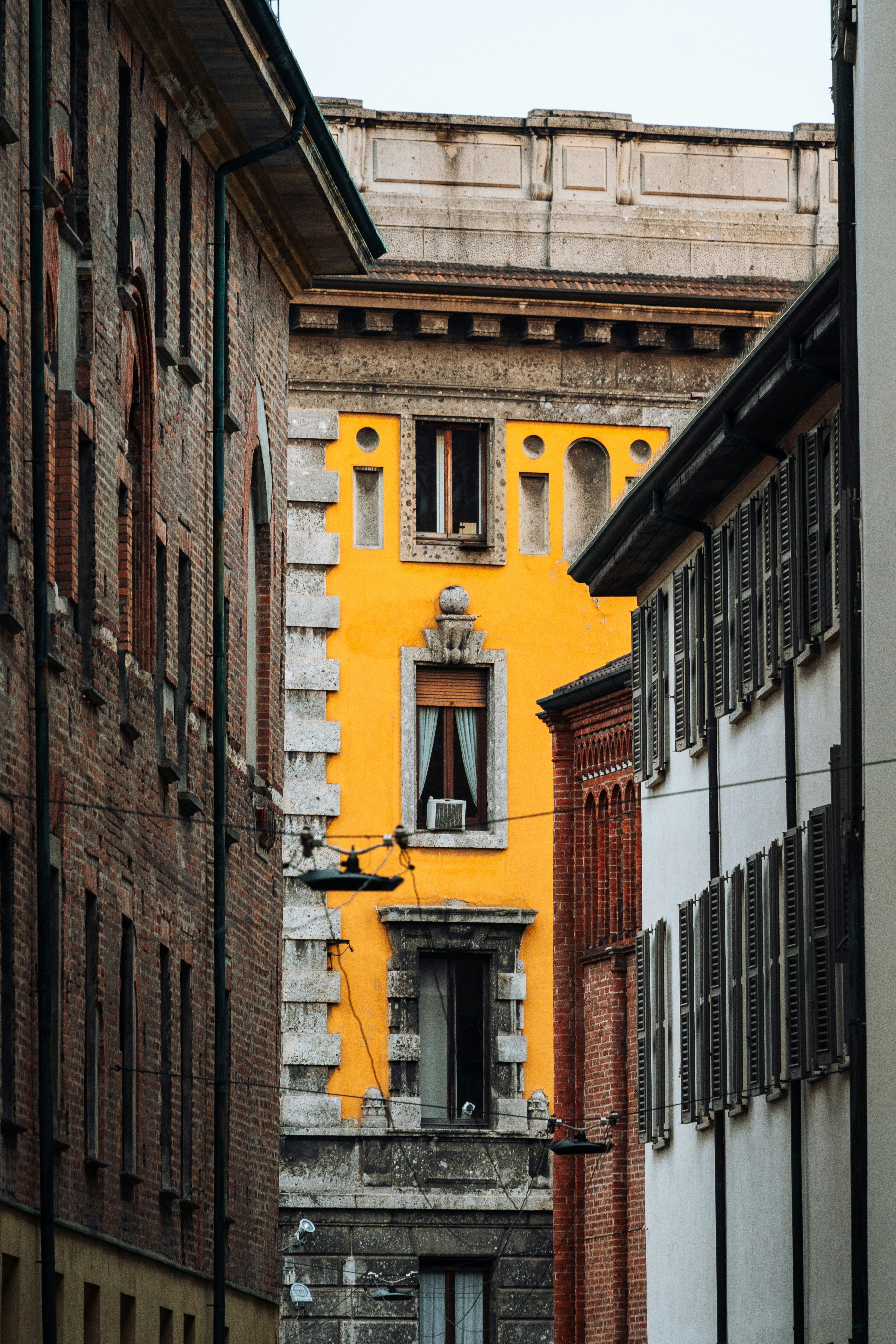 Yellow Facade Anchoring a Narrow Brick Alley