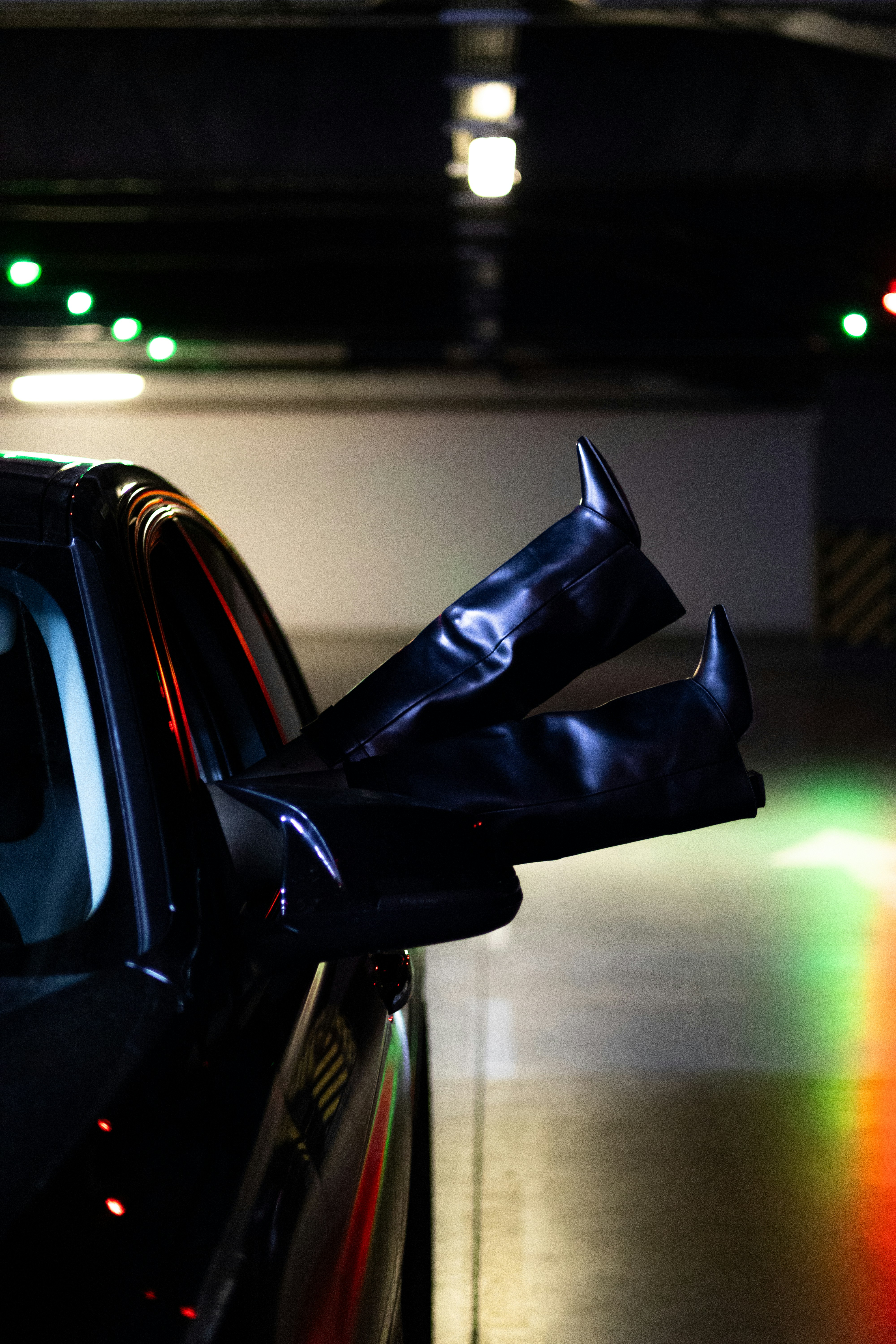 Boots Dangling from a Car Window in a Dim Underground Parking Garage
