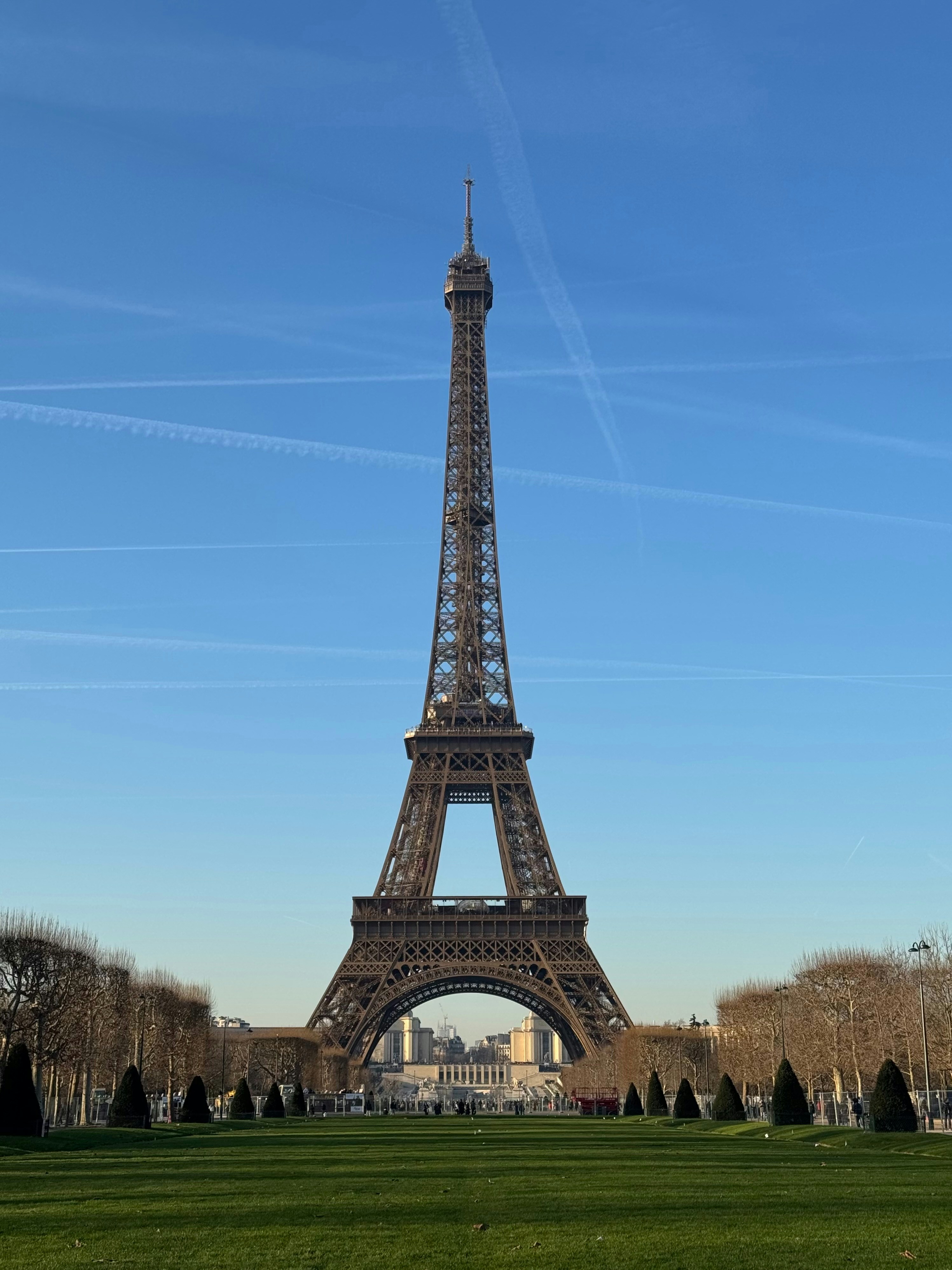 Iron Lace Reaches Skyward: Eiffel Tower Framed by Crisscrossed Contrails
