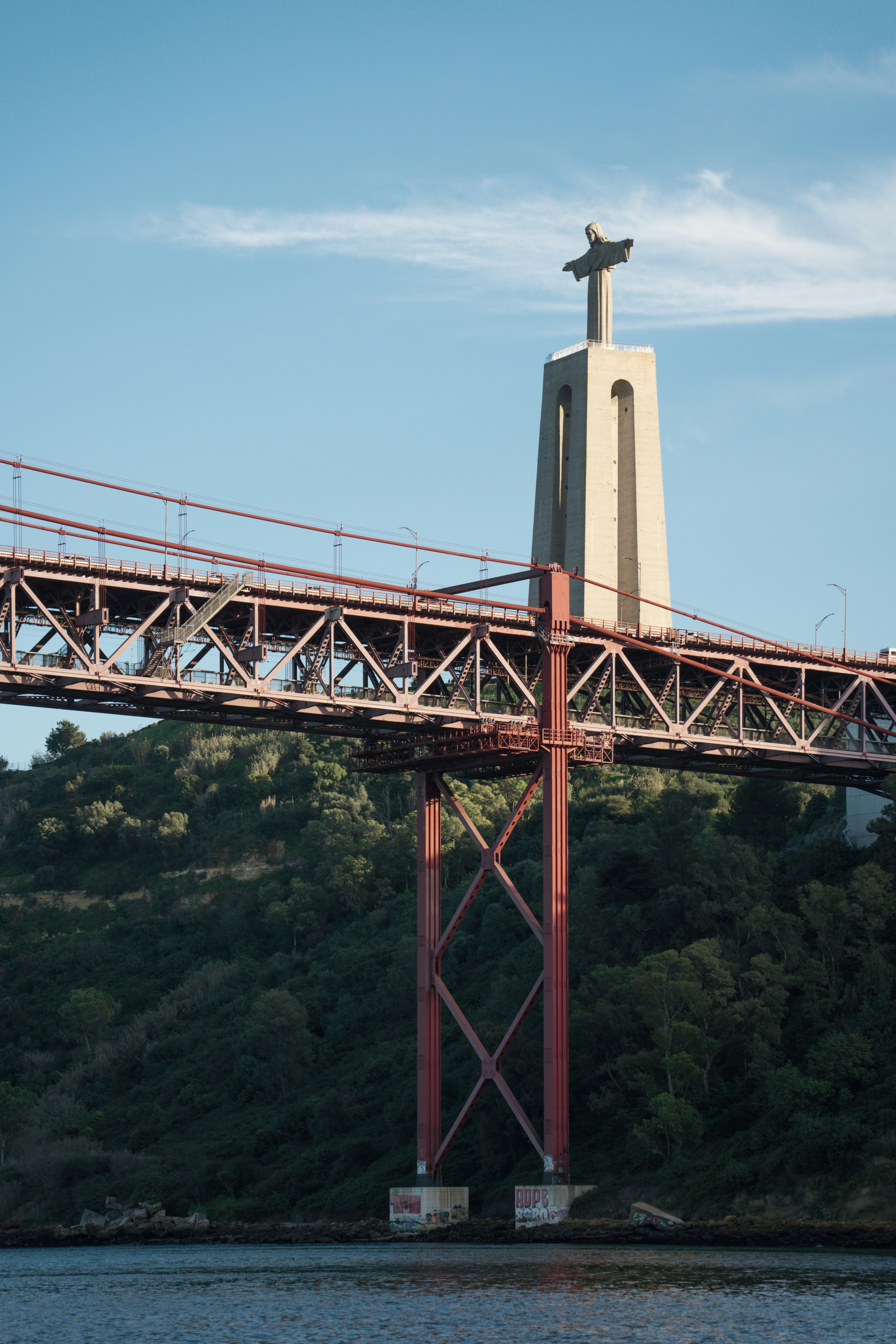 Winged Sentinel Over Red Steel: A River Bridge Crowned by a Monument