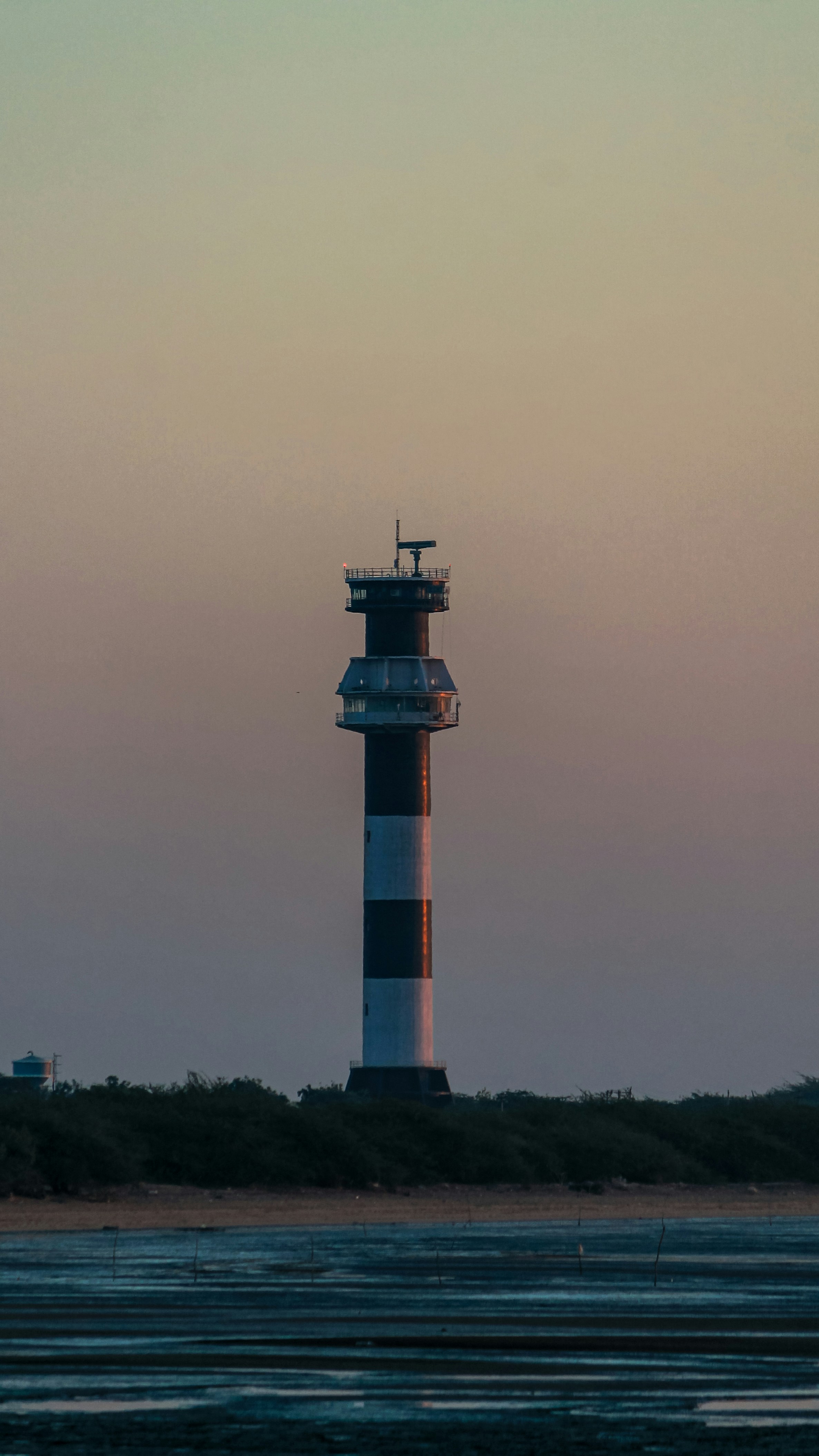 Dusk Sentinel: The Striped Lighthouse Guarding a Quiet Shore