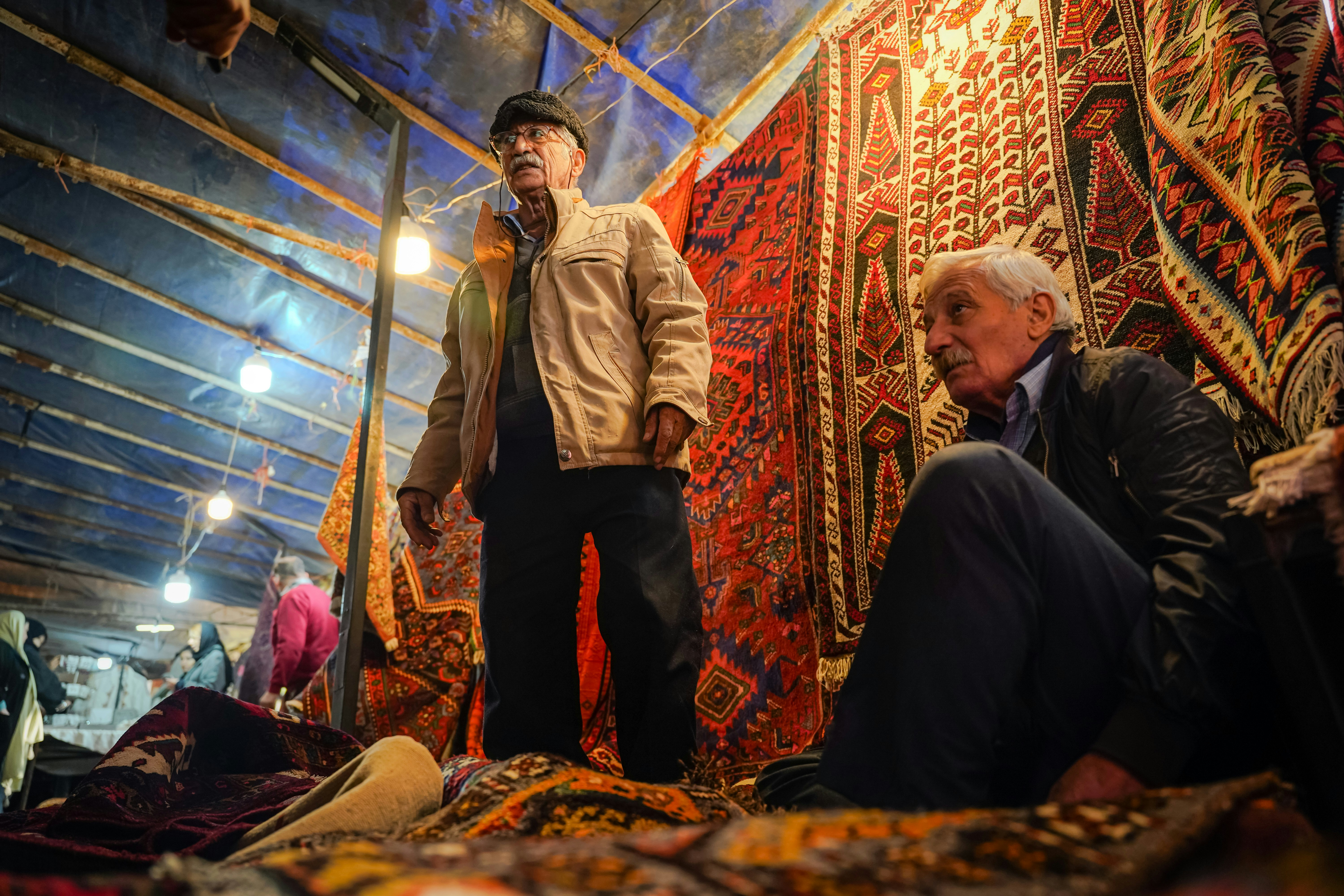A group of men standing around a pile of rugs photo – Free Portrait ...