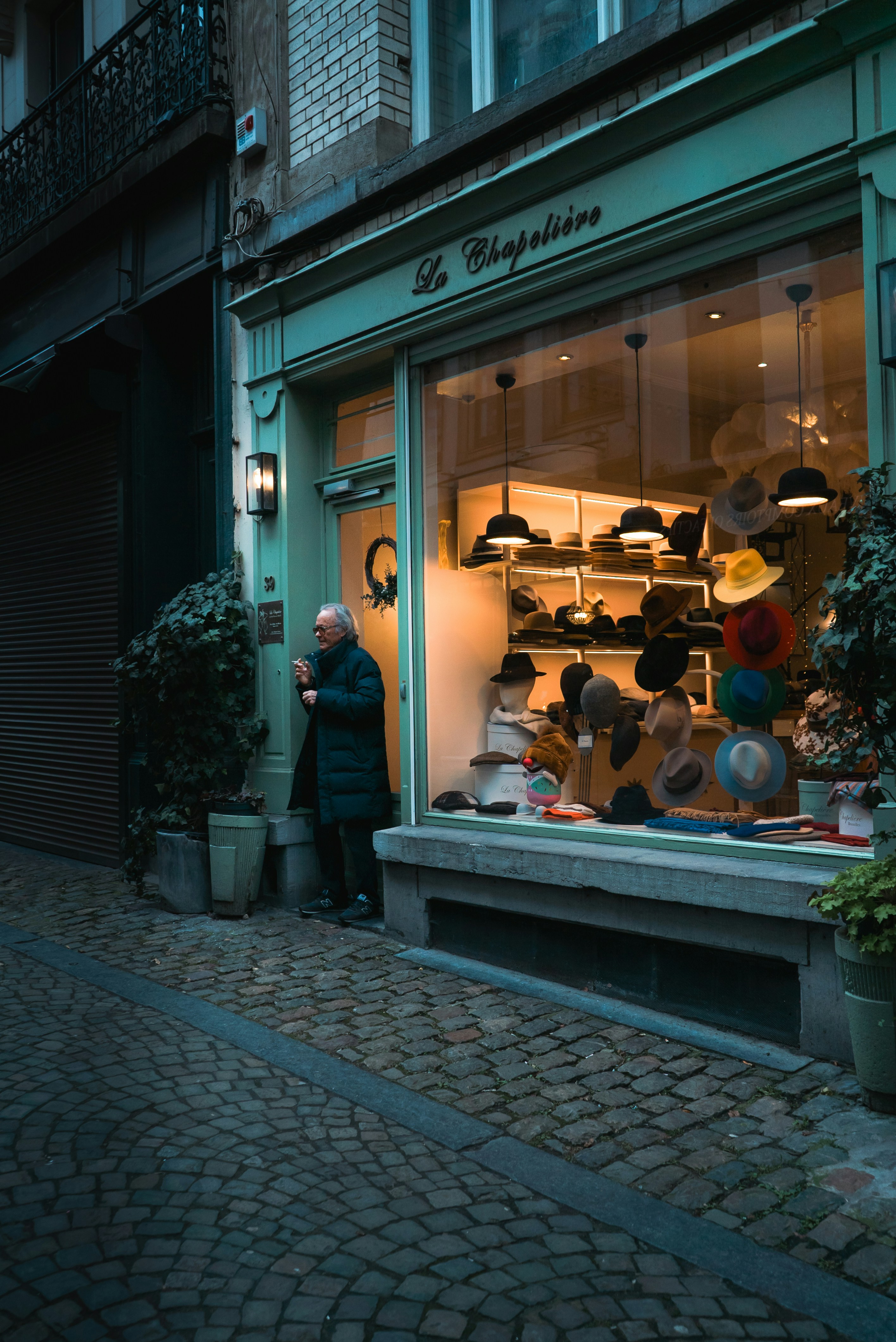 Hats under amber glow: a cobbled street shopfront