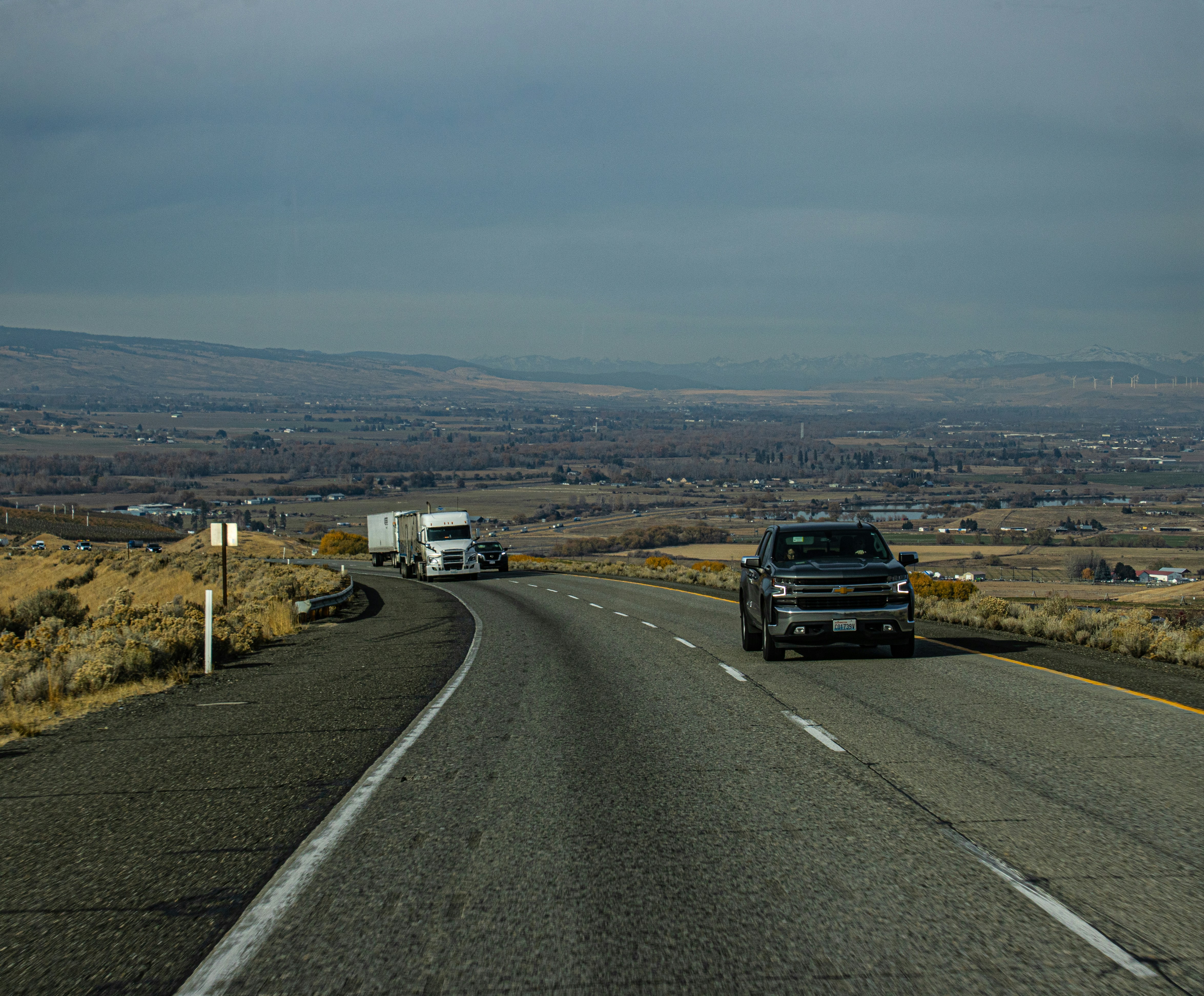 A truck driving down a road next to a field photo – Free Cars Image on ...